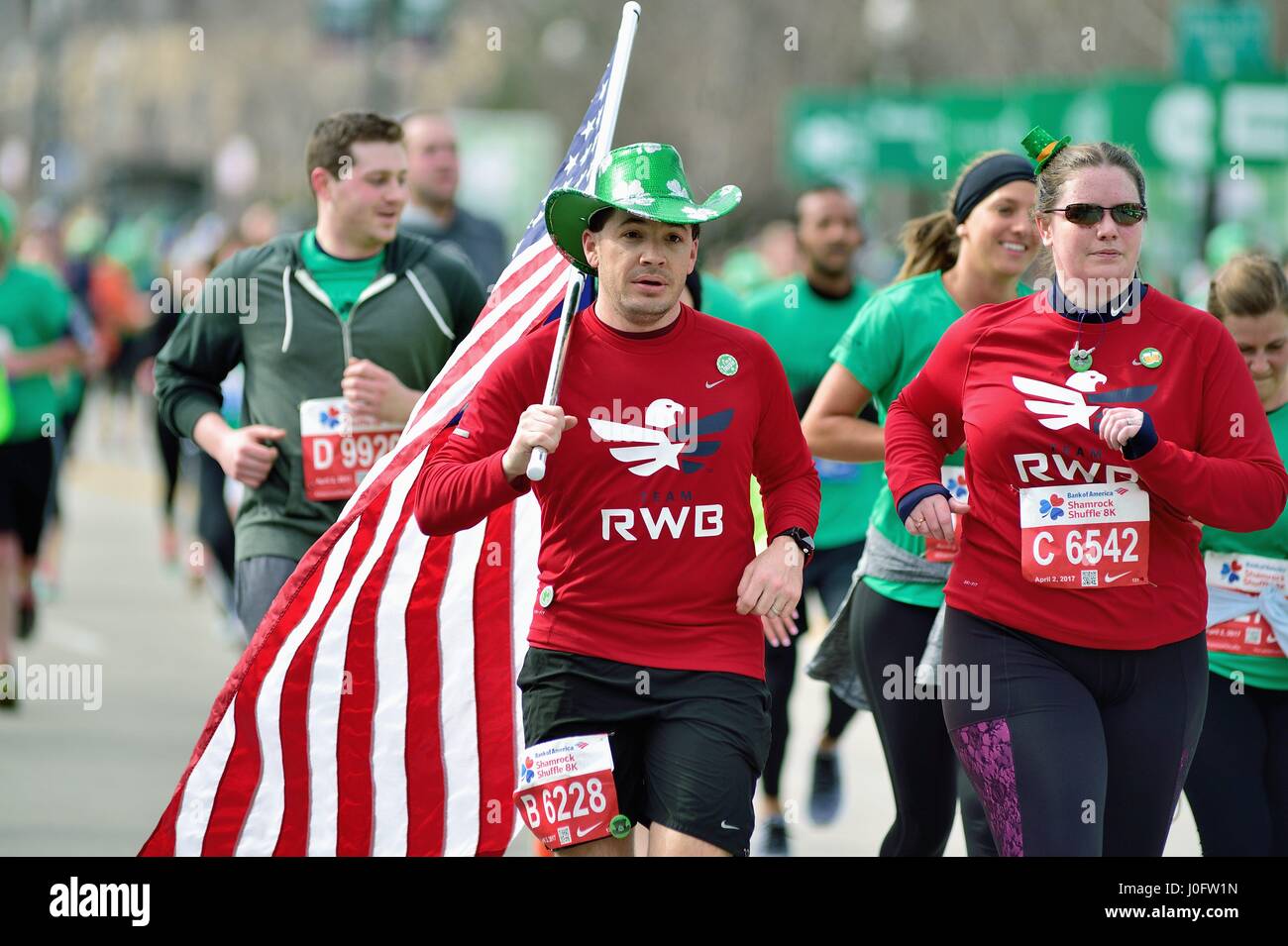Among a sea of runners a man carries an American flag as he approached ...