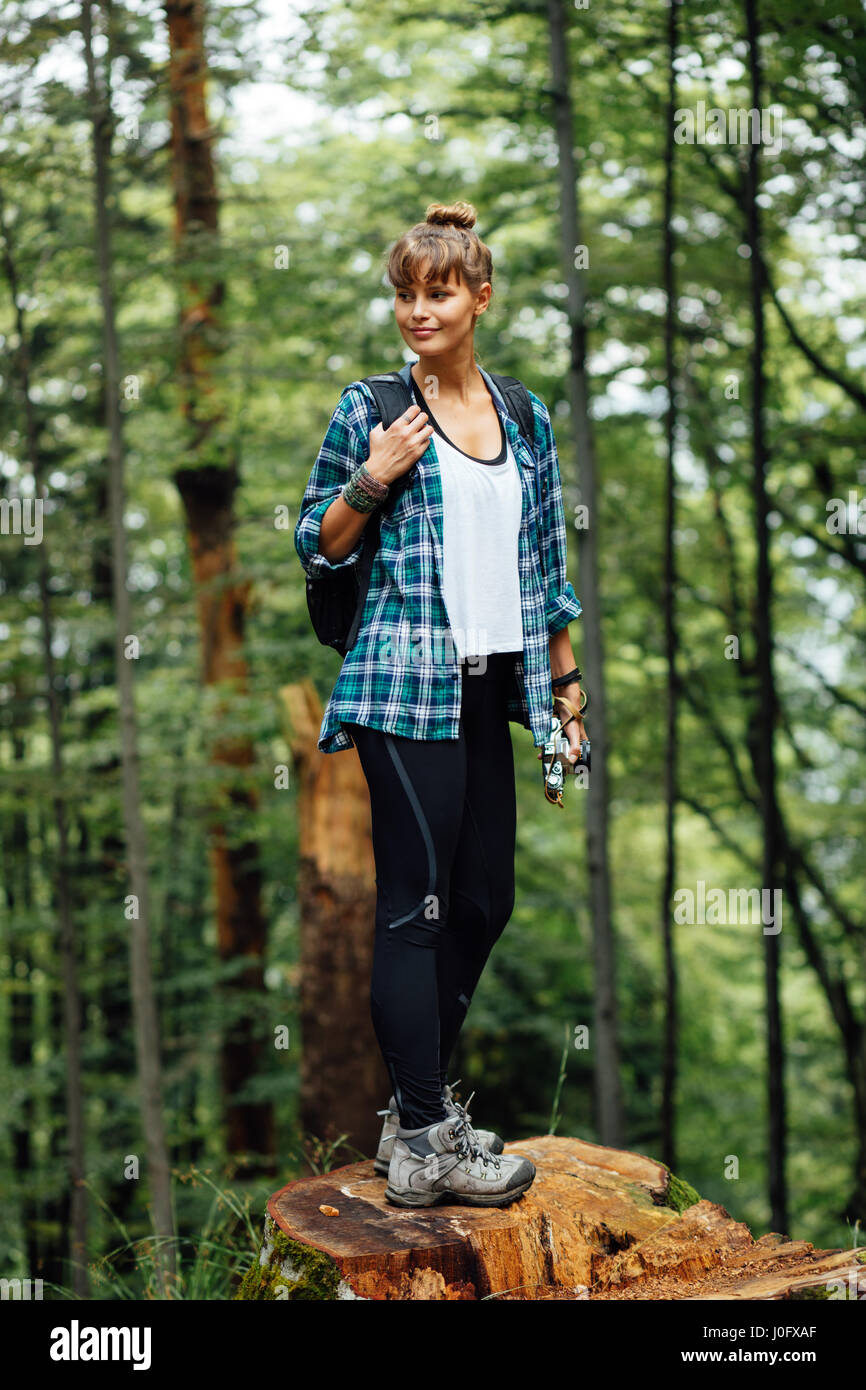 single traveler woman sitting on a log with her backpack and camera in ...