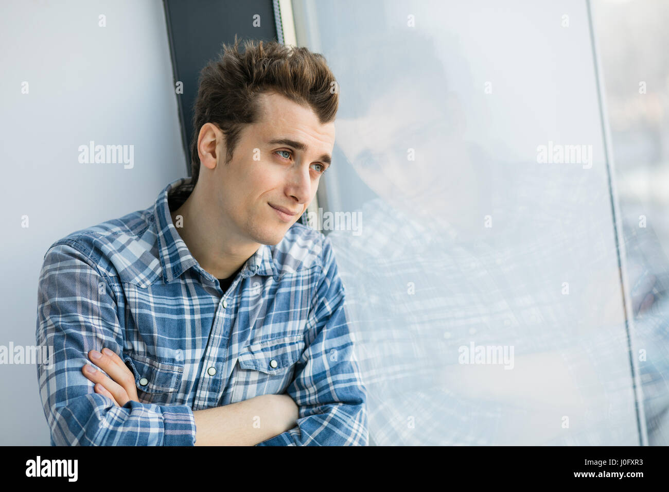 handsome young man leaning his head against the window of a large ...