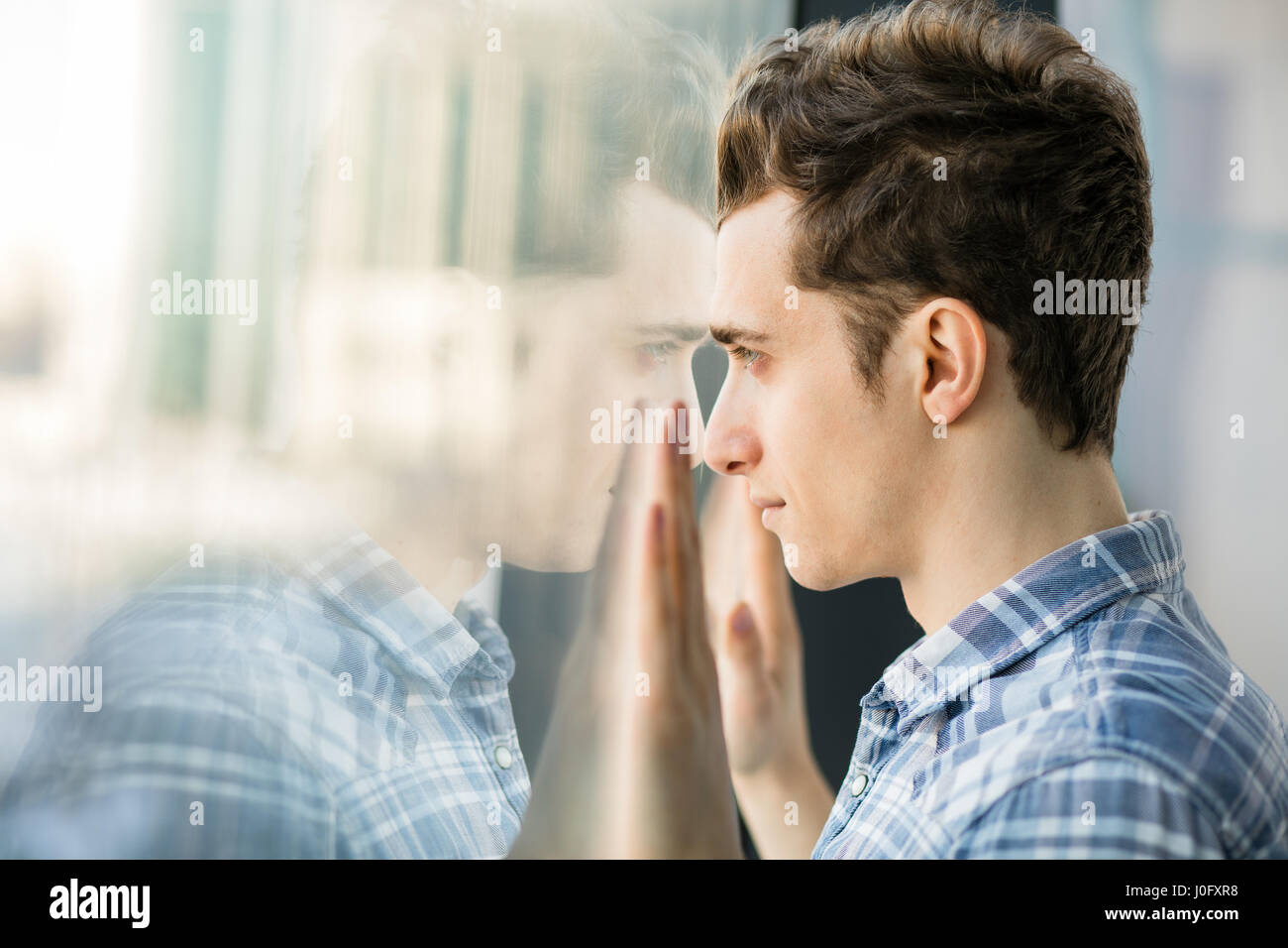 handsome young man leaning his head against the window of a large ...