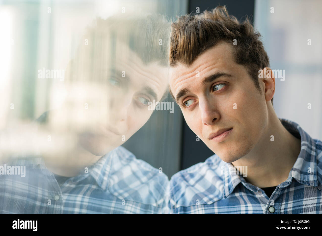handsome young man leaning his head against the window of a large ...