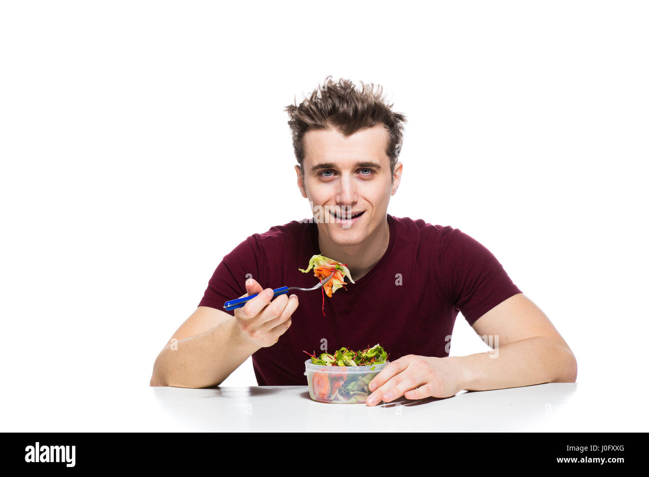 young healthy man eating salad and looking happy and strong, isolated ...