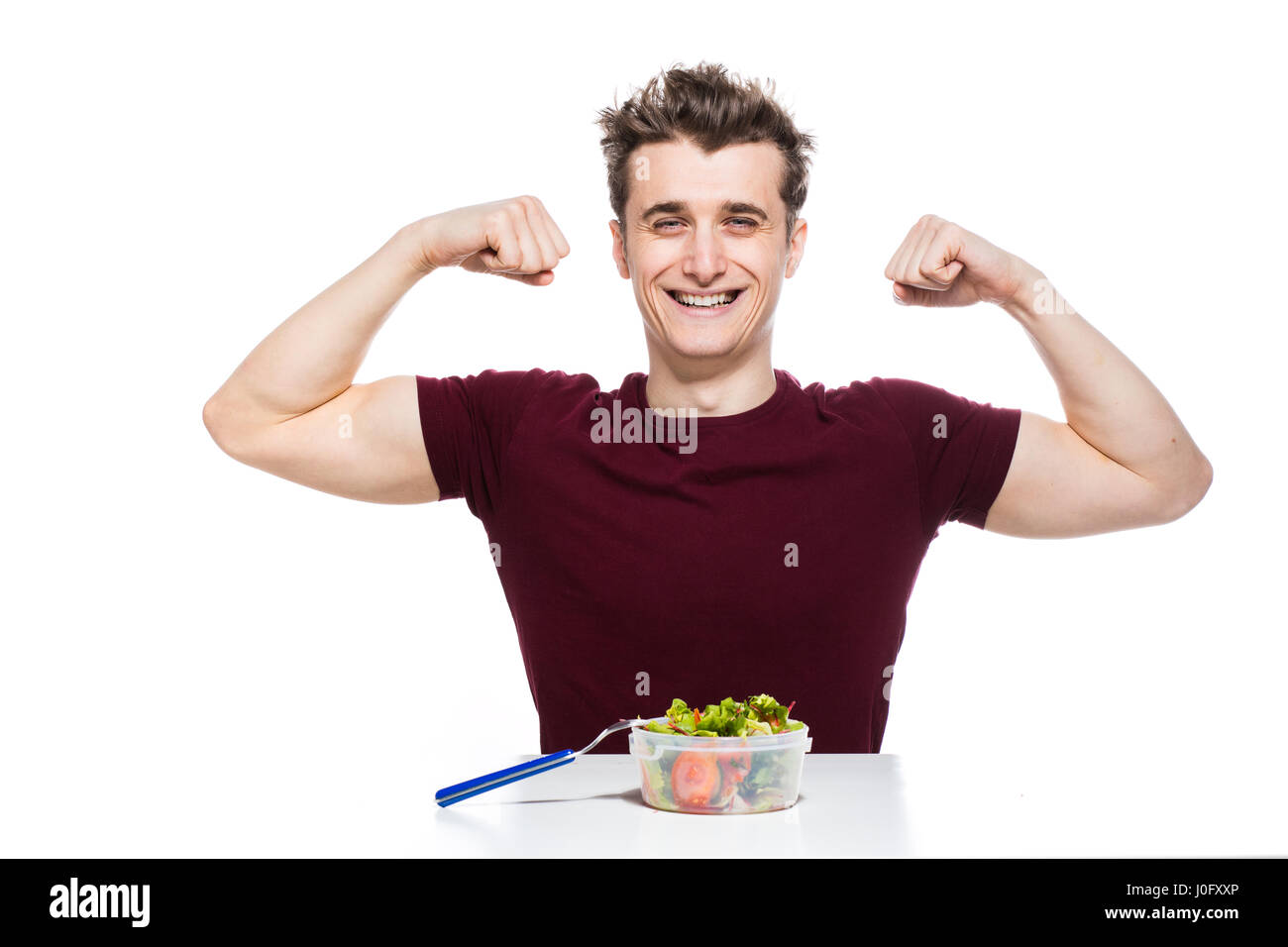young healthy man eating salad and looking happy and strong, isolated ...