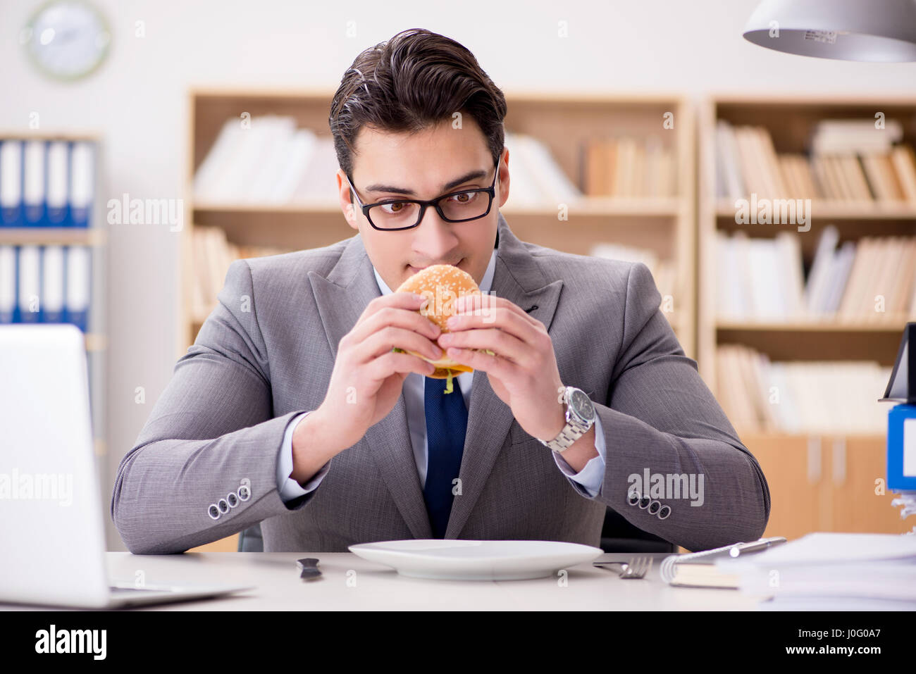 Hungry funny businessman eating junk food sandwich Stock Photo - Alamy