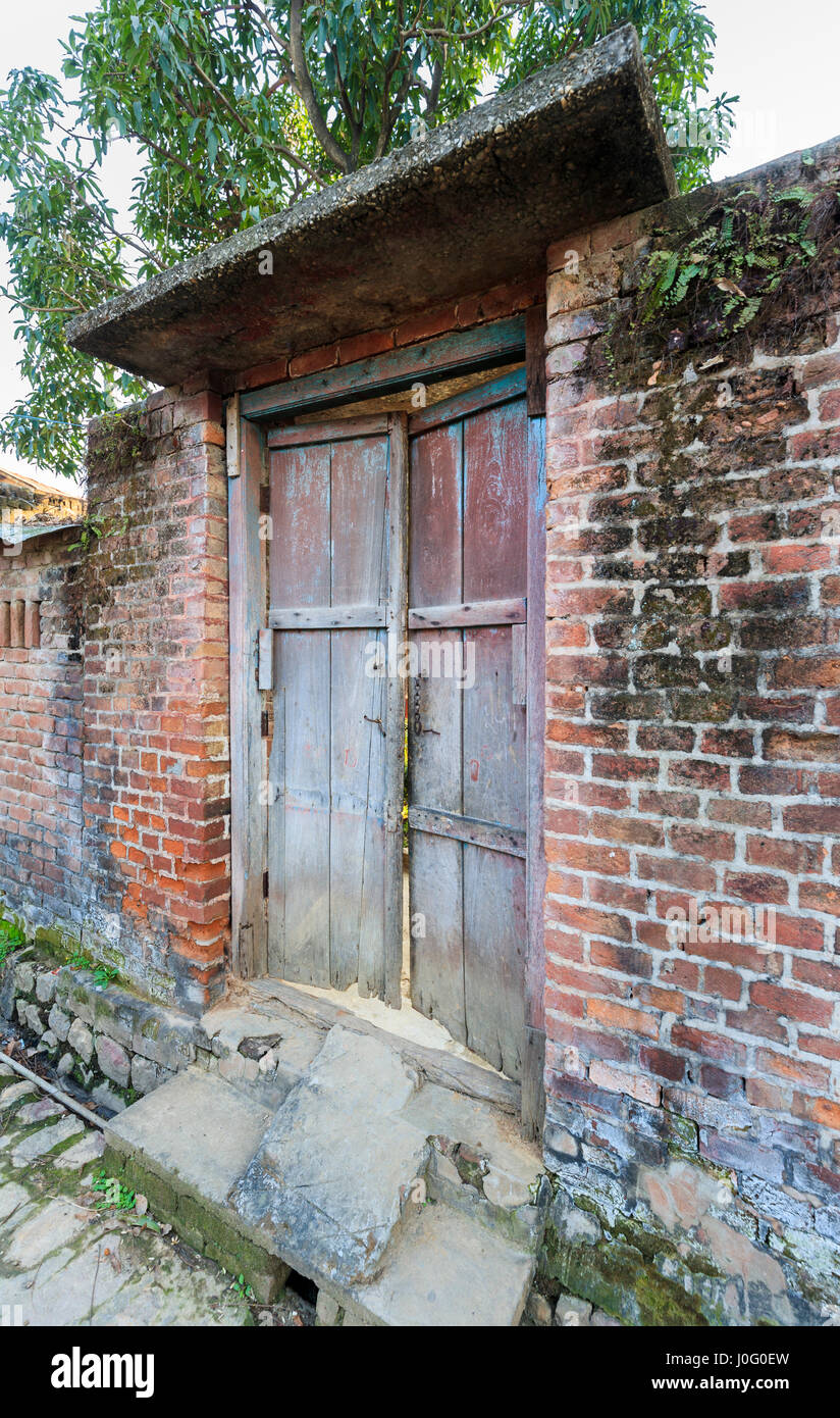 Rotting wooden doors in a doorway in a red brick wall, Pragpur, a ...