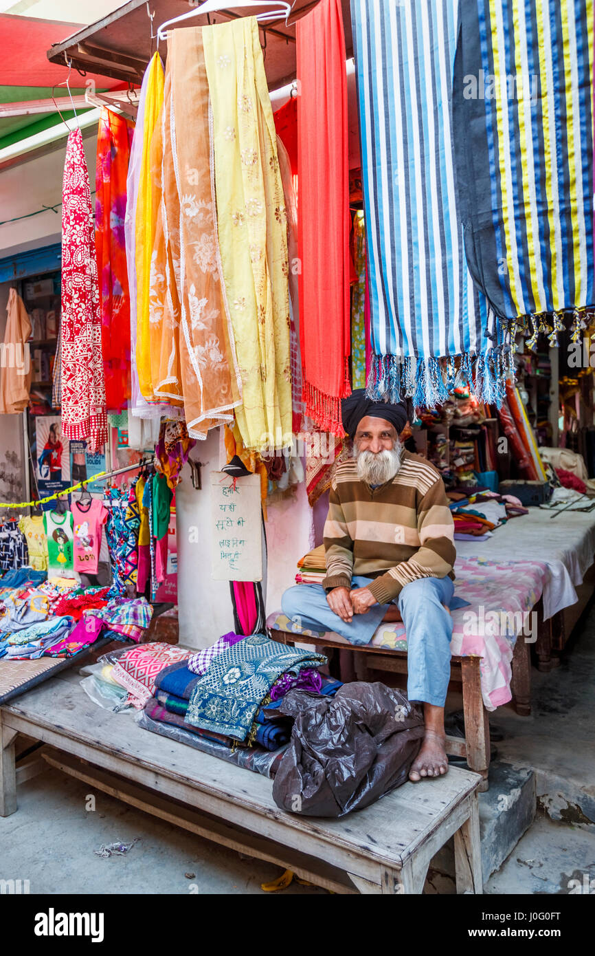 Male bearded Sikh shopkeeper in a colourful fabric shop wearing typical ...