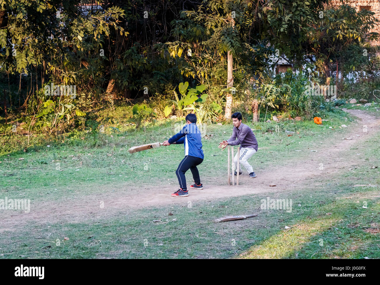 Two local Indian boys having fun playing a game of cricket on a dusty ...