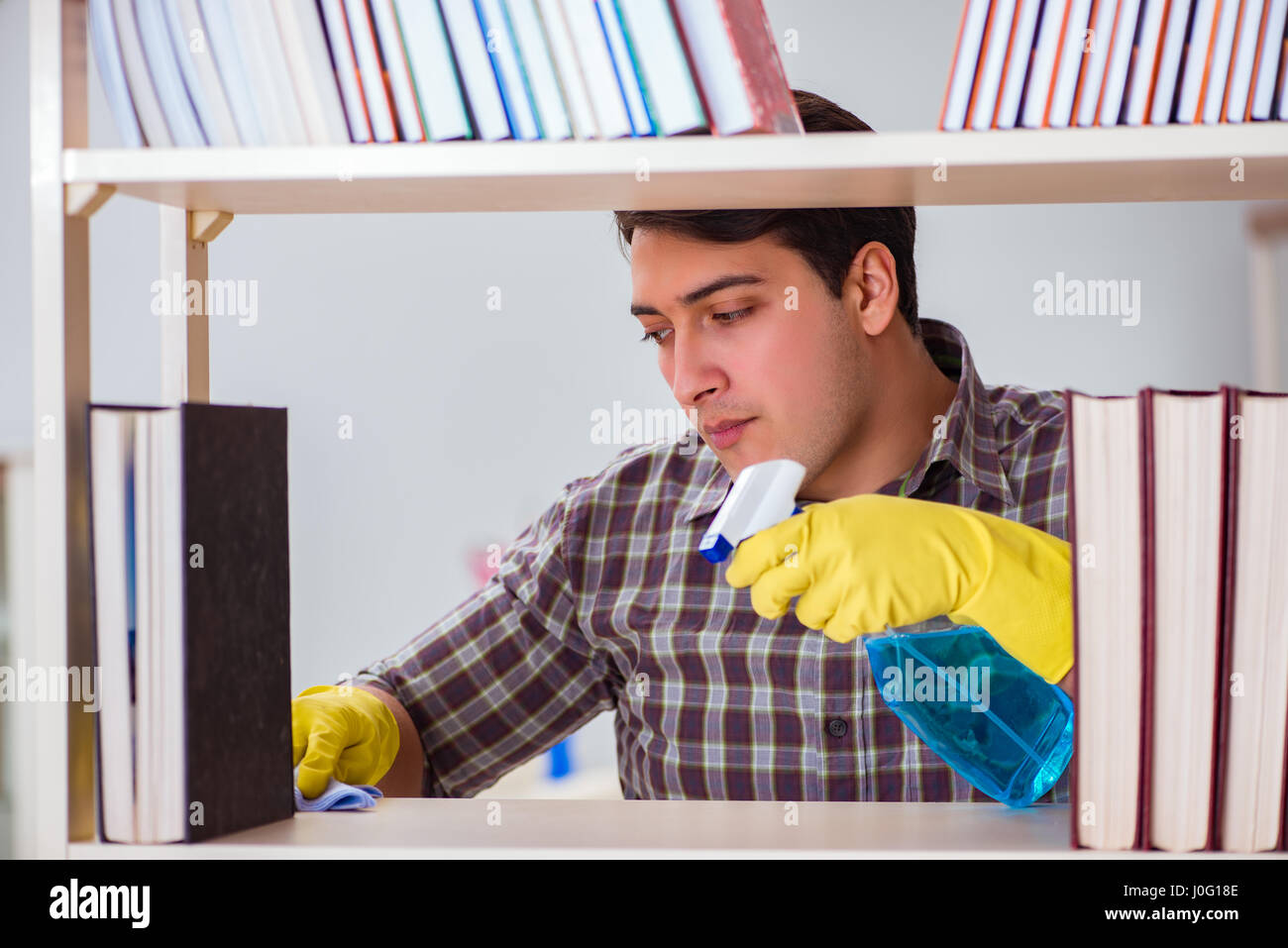 Man cleaning dust from bookshelf Stock Photo - Alamy