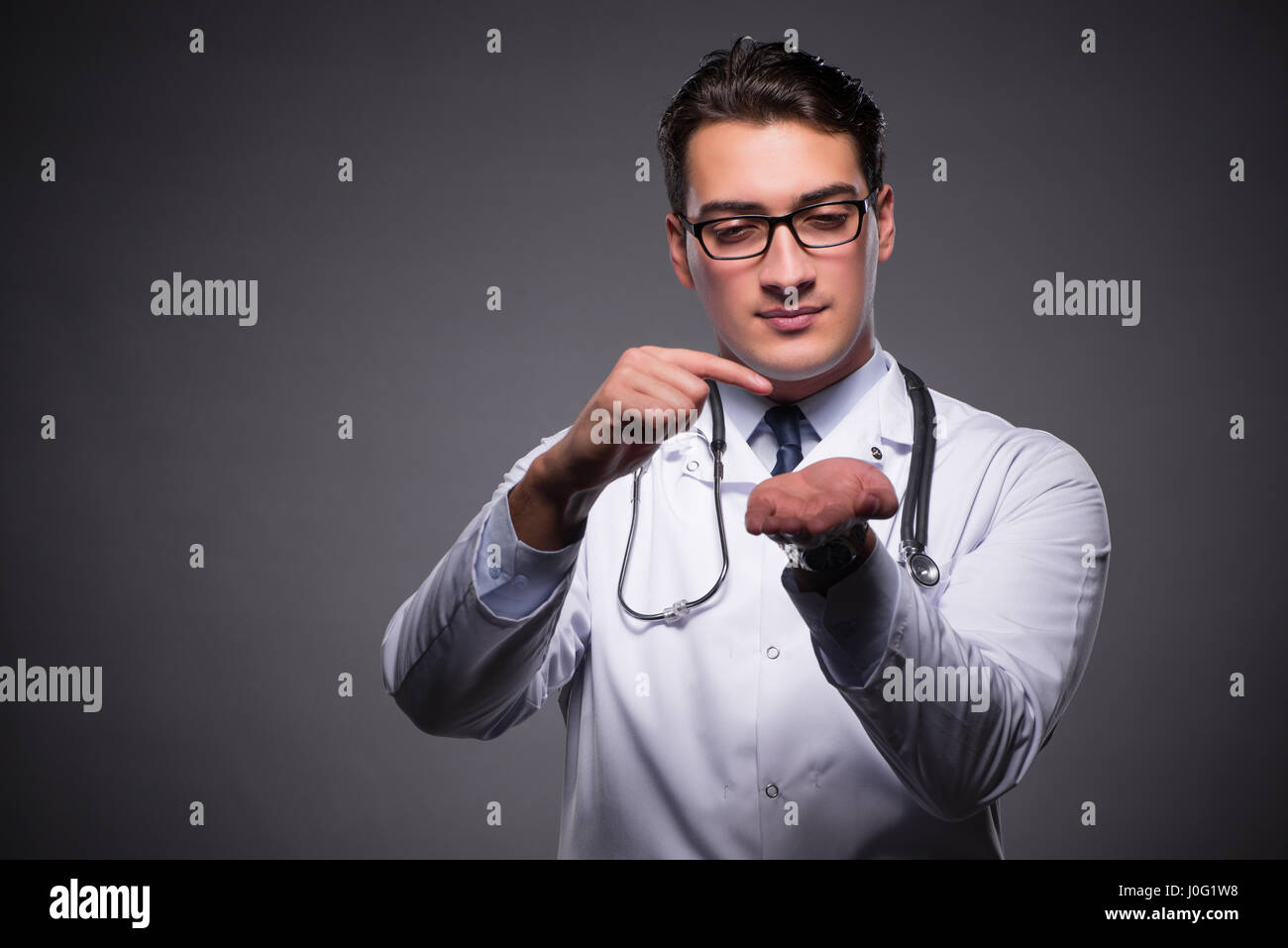 Young doctor against dark background Stock Photo - Alamy