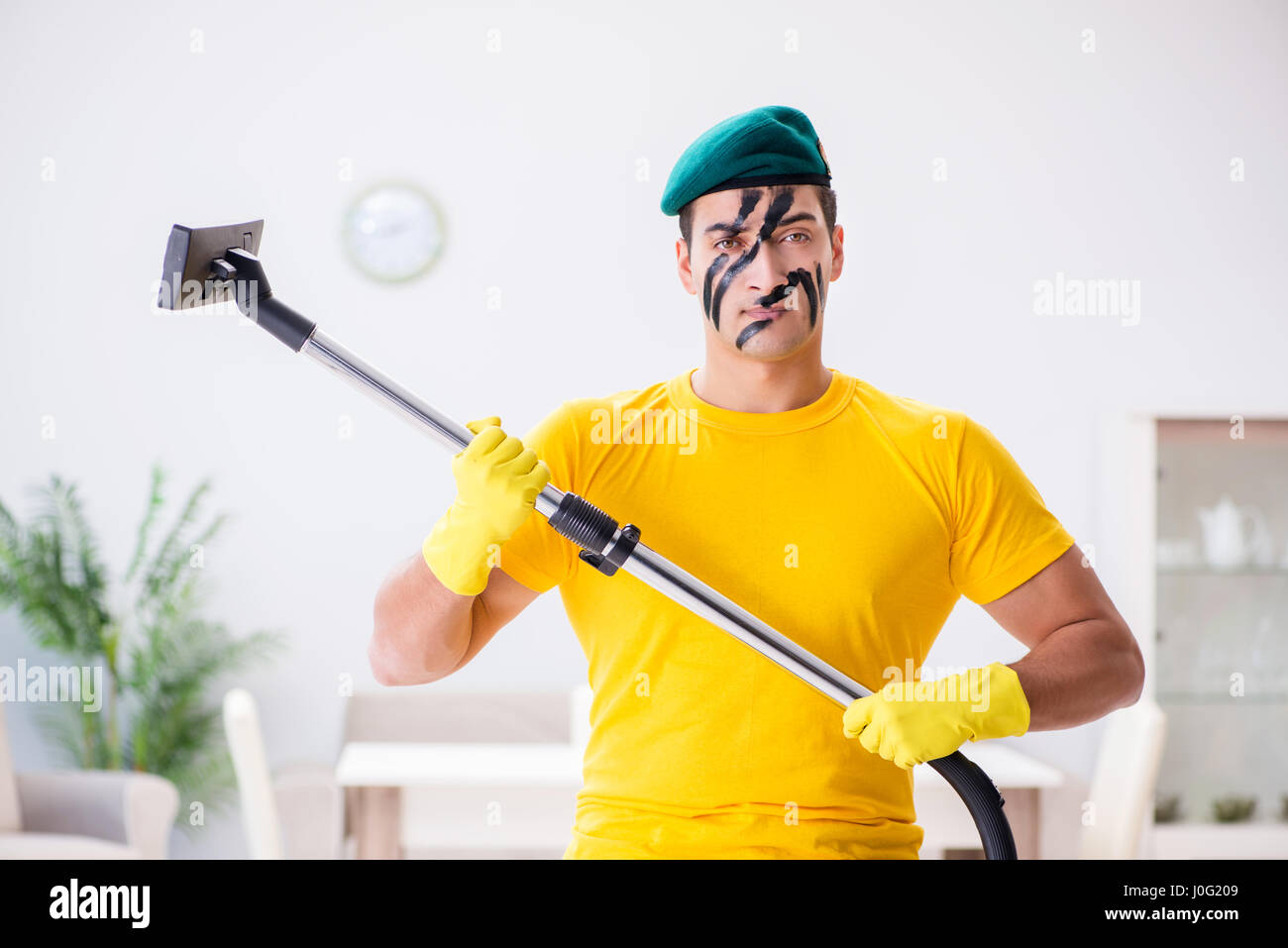 Funny man in military style cleaning the house Stock Photo - Alamy