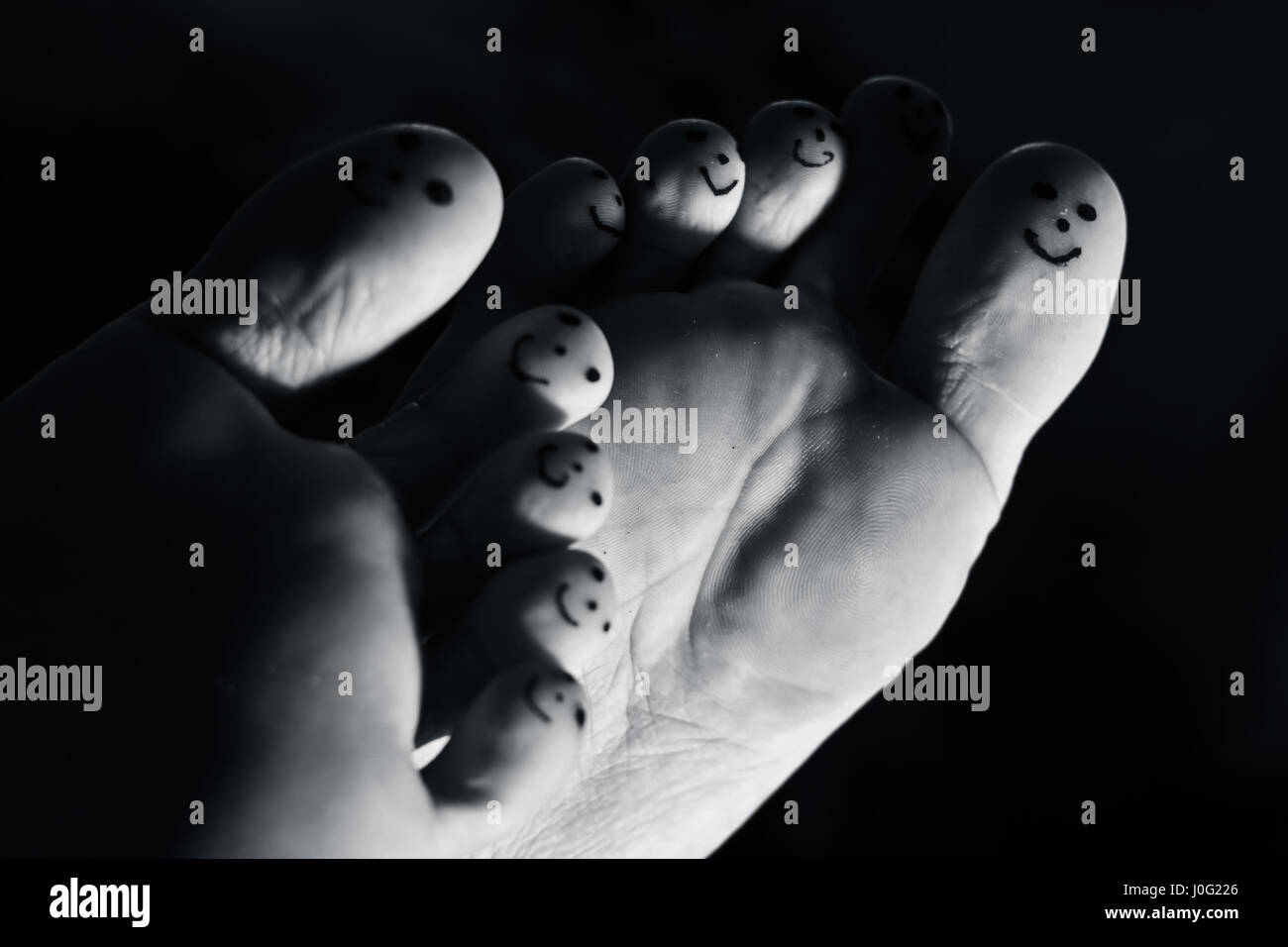 Smiley faces drawn on human foot with black pen Stock Photo - Alamy