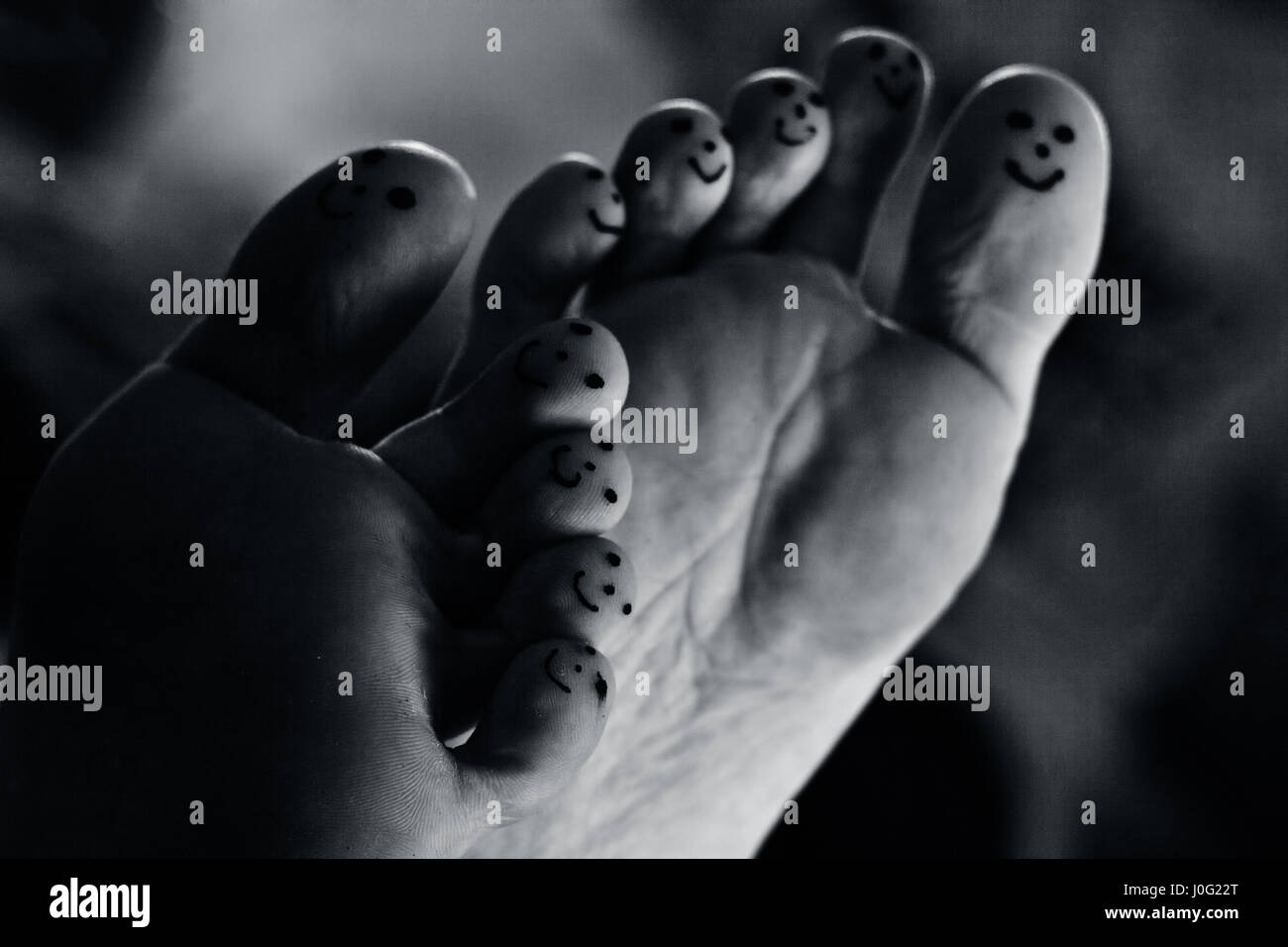 Smiley faces drawn on human foot with black pen Stock Photo - Alamy