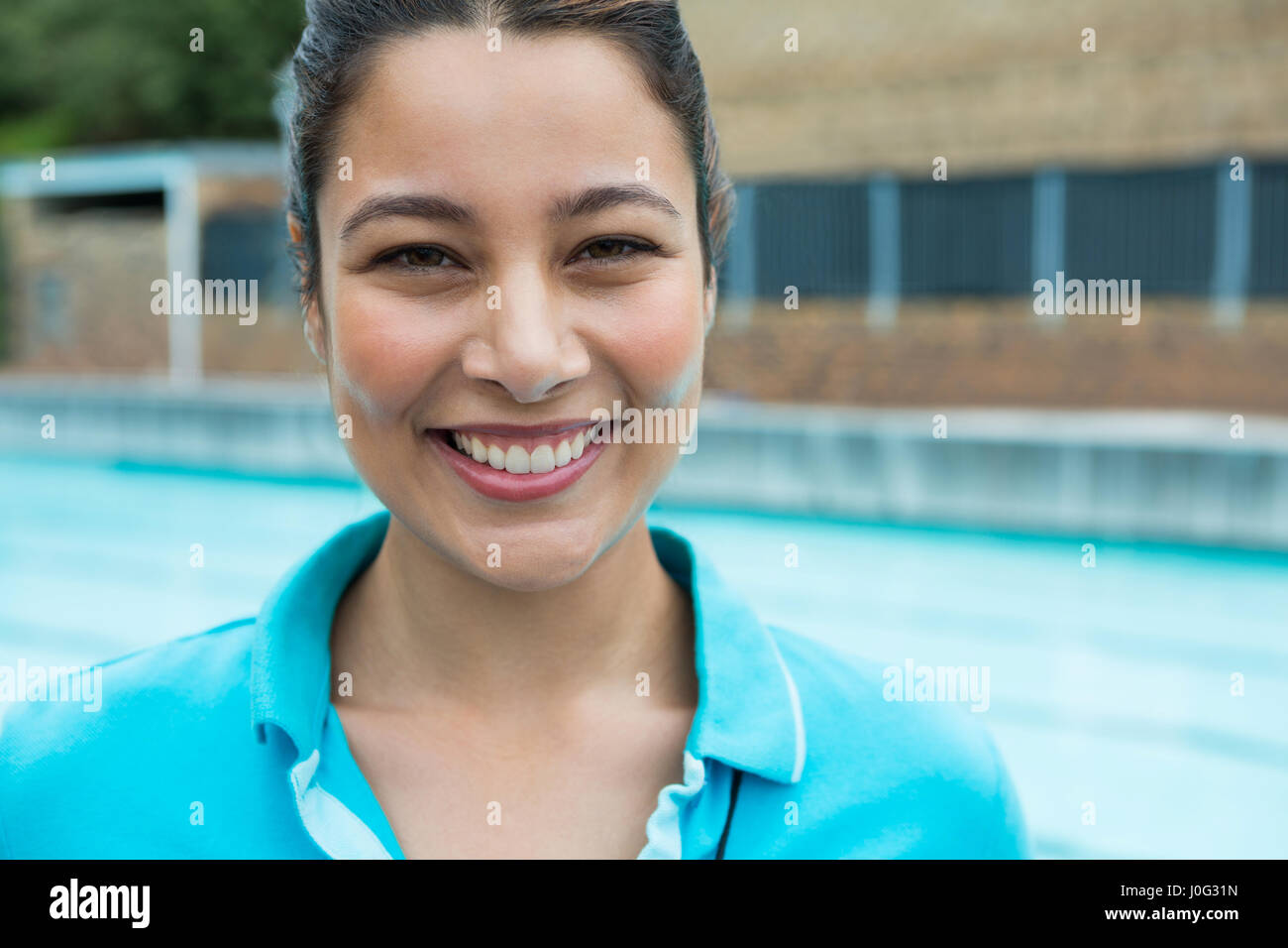 Portrait of smiling female coach standing near poolside at the leisure ...