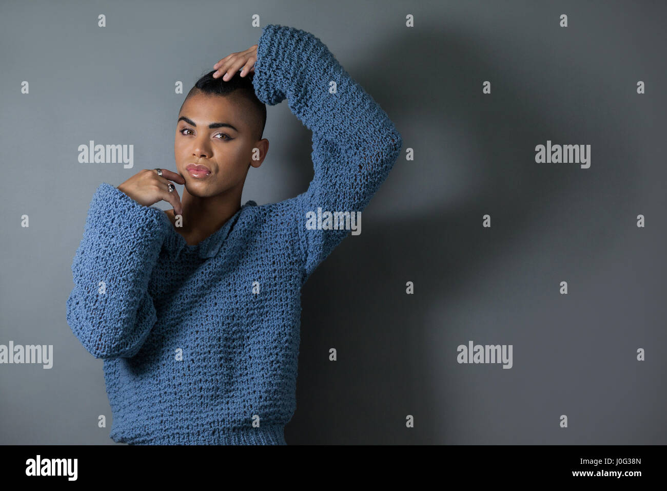 Portrait of confident transgender posing while standing over gray ...
