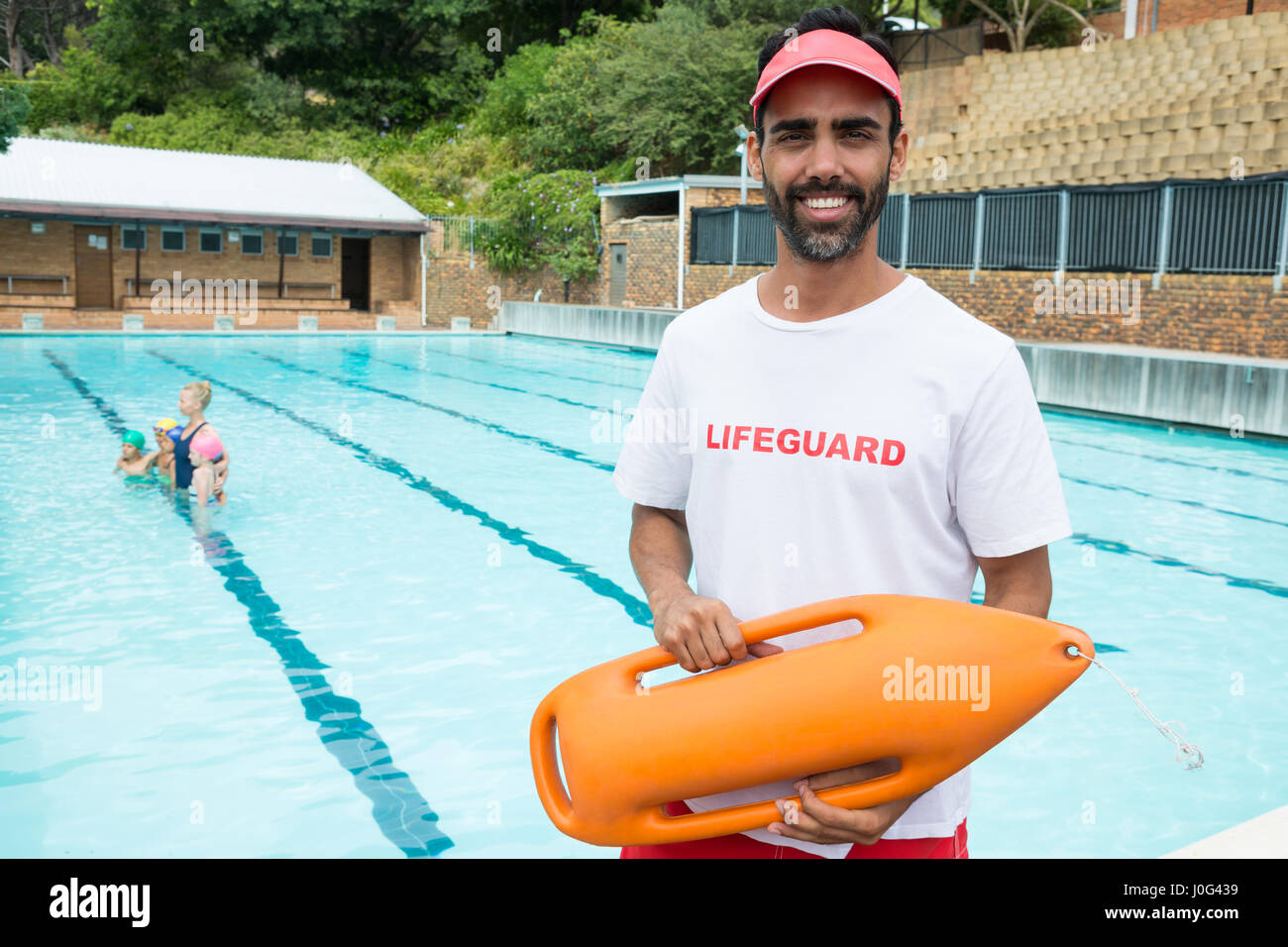 Portrait of lifeguard standing with rescue buoy near poolside Stock ...