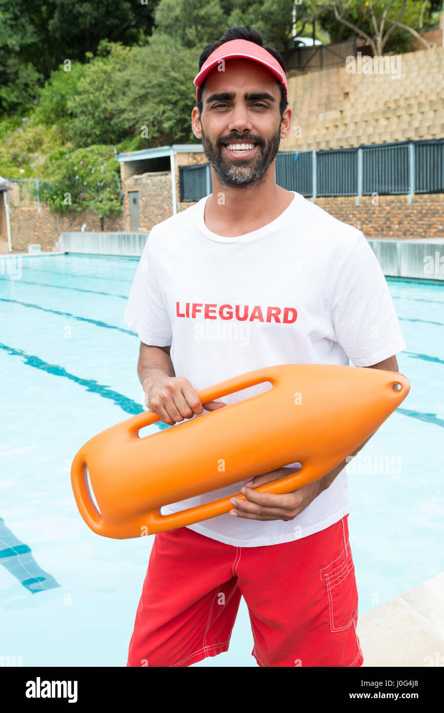 Portrait of lifeguard standing with rescue buoy near poolside Stock ...