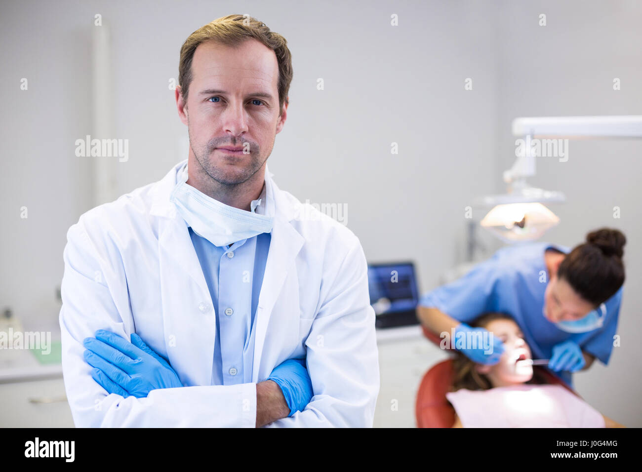 Portrait of dentist standing with arms crossed in clinic Stock Photo ...
