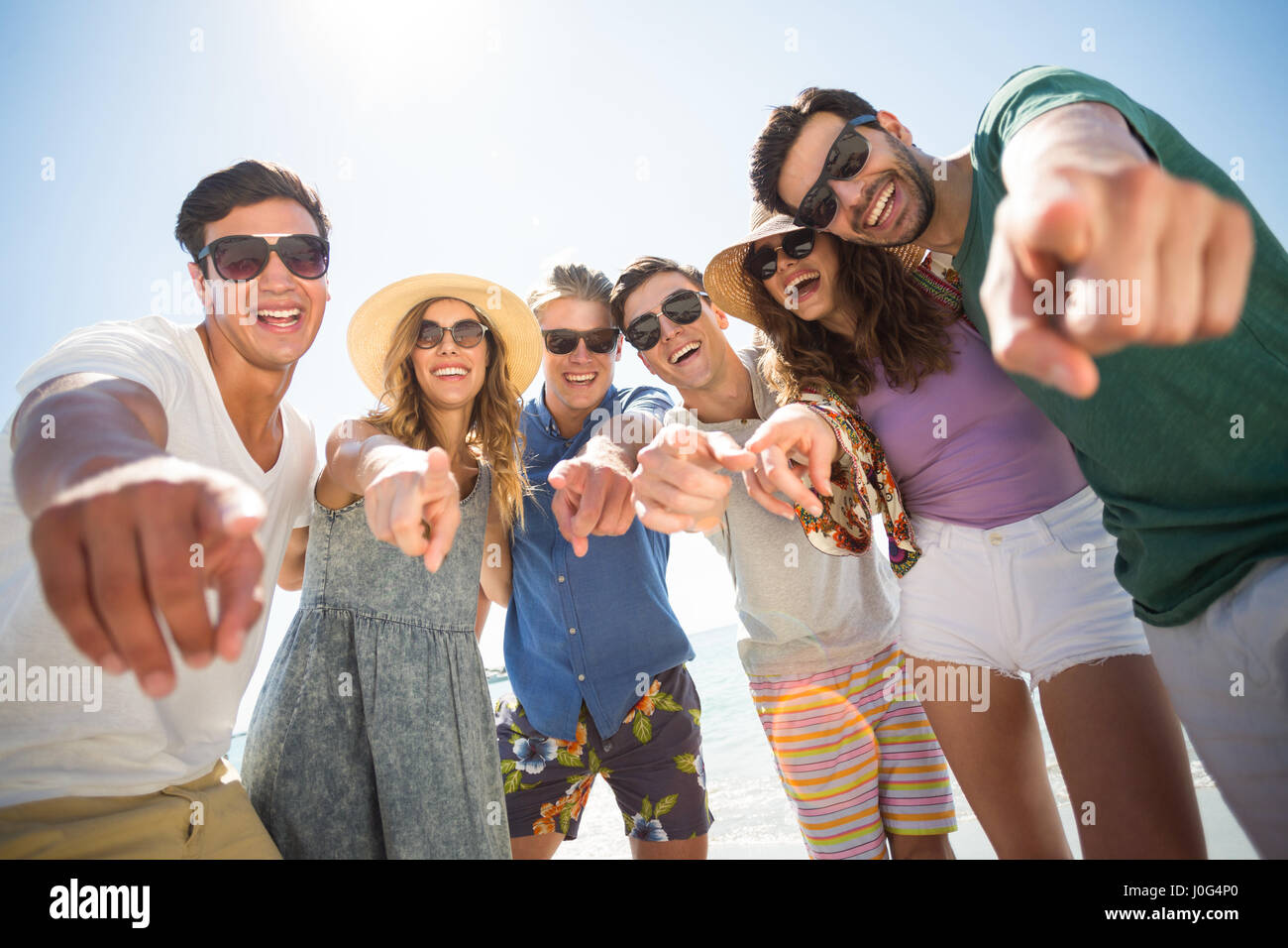 Cheerful friends pointing while standing against sky on sunny day Stock ...