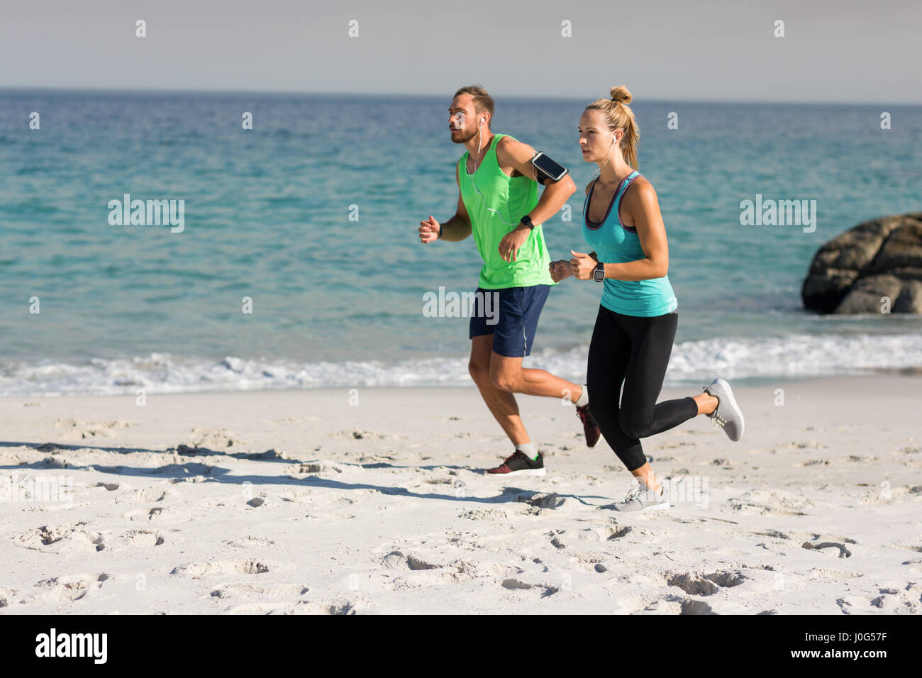 Full length of young couple jogging at beach Stock Photo - Alamy