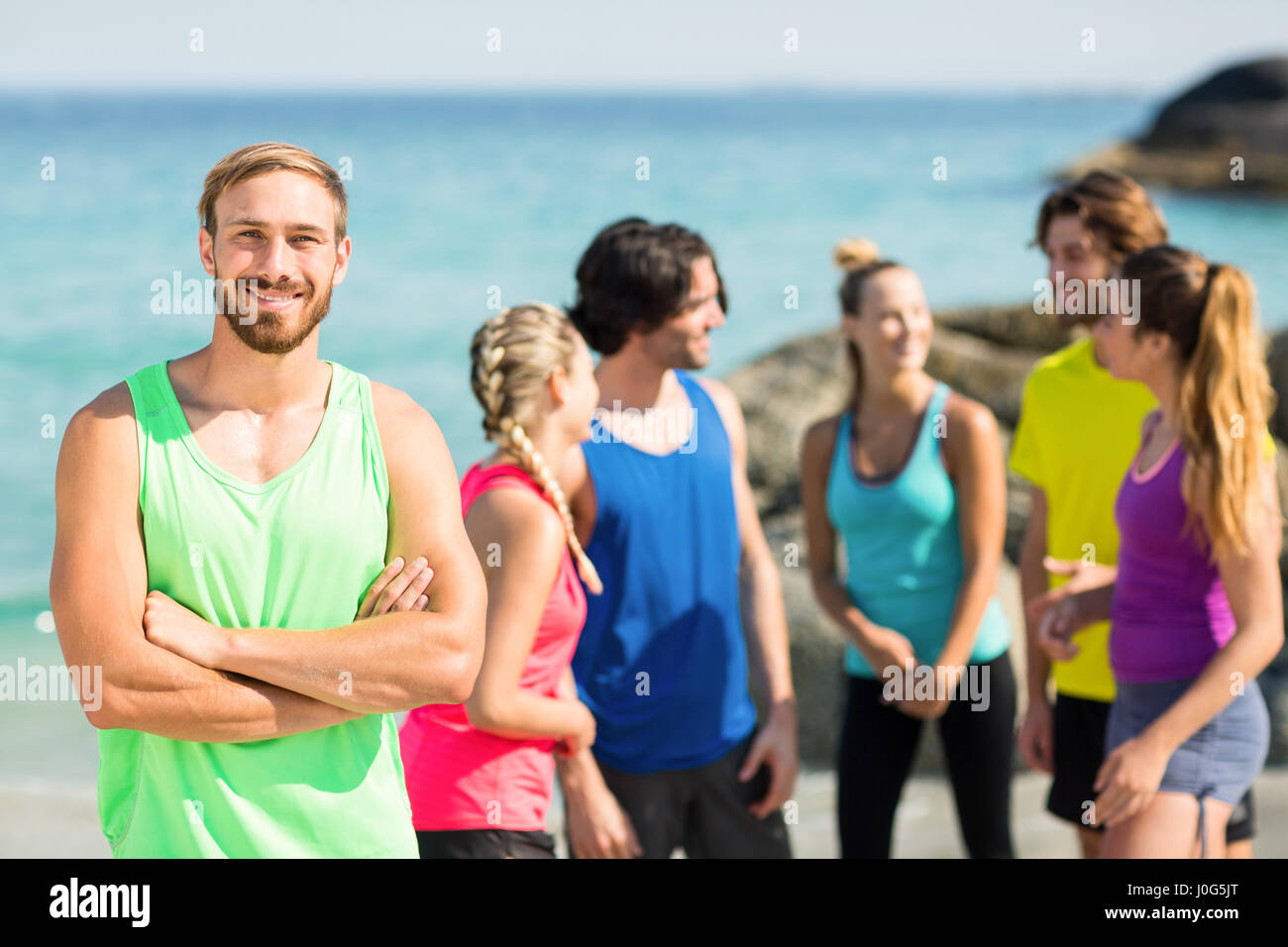 Smiling friends standing on shore at beach Stock Photo - Alamy