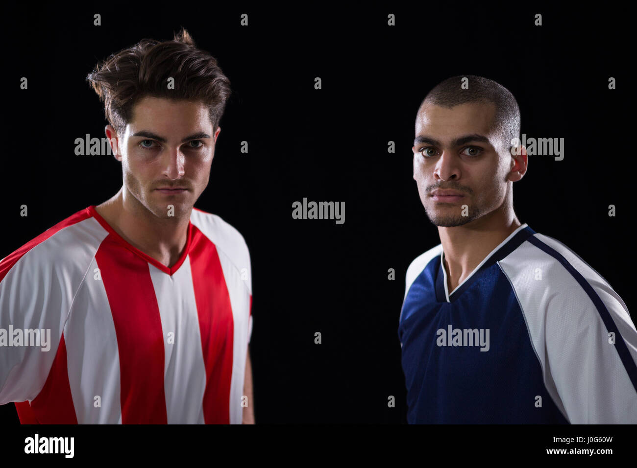 Portrait of two football players standing against black background ... Portrait of two football players standing against black background ...