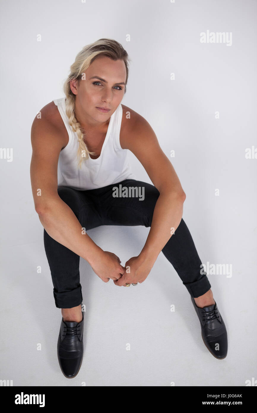 High angle portrait of transgender woman sitting over gray background ...