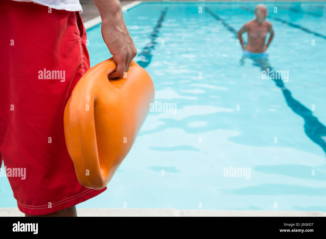 Mid section of lifeguard holding rescue buoy at poolside Stock Photo ...