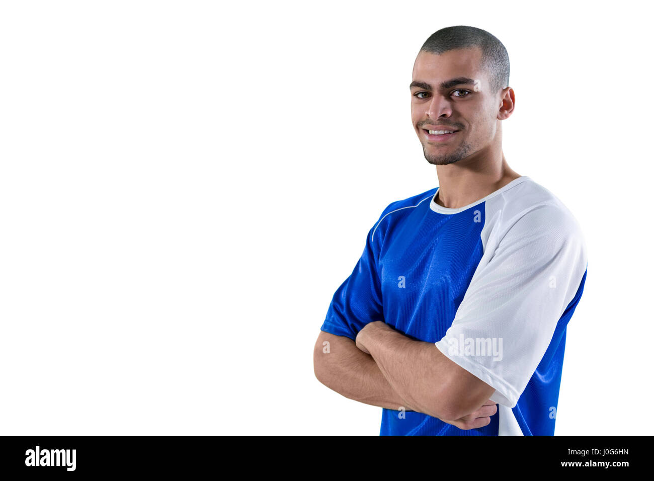 Portrait of football player standing with arms crossed against white ...
