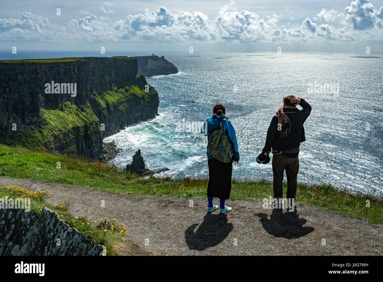 Two walkers on the cliff-top path at the Cliffs of Moher, looking south ...