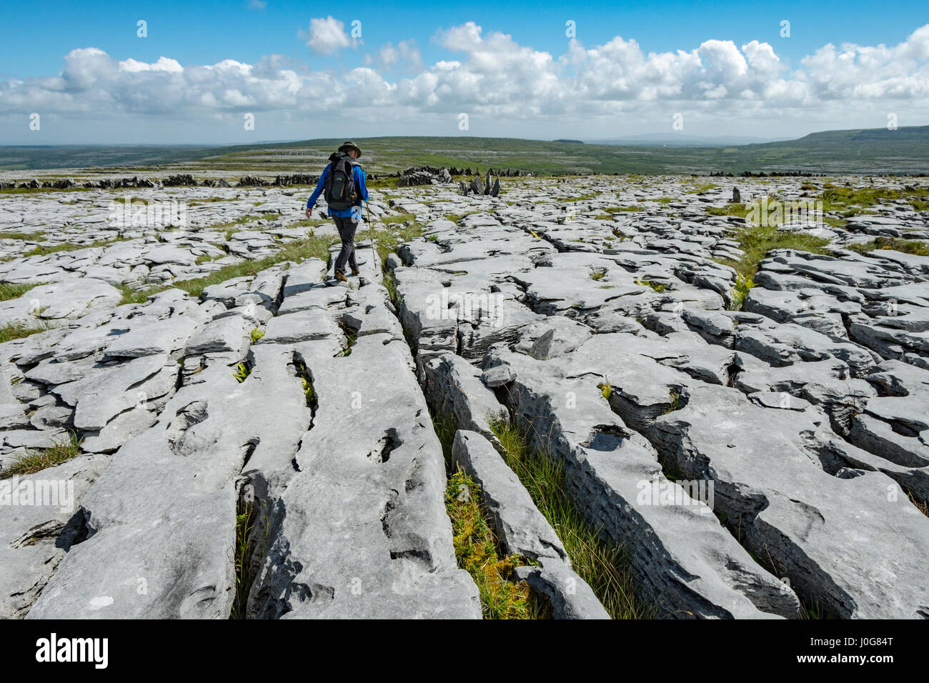 A walker on limestone pavement on the plateau of Gleninagh Mountain ...