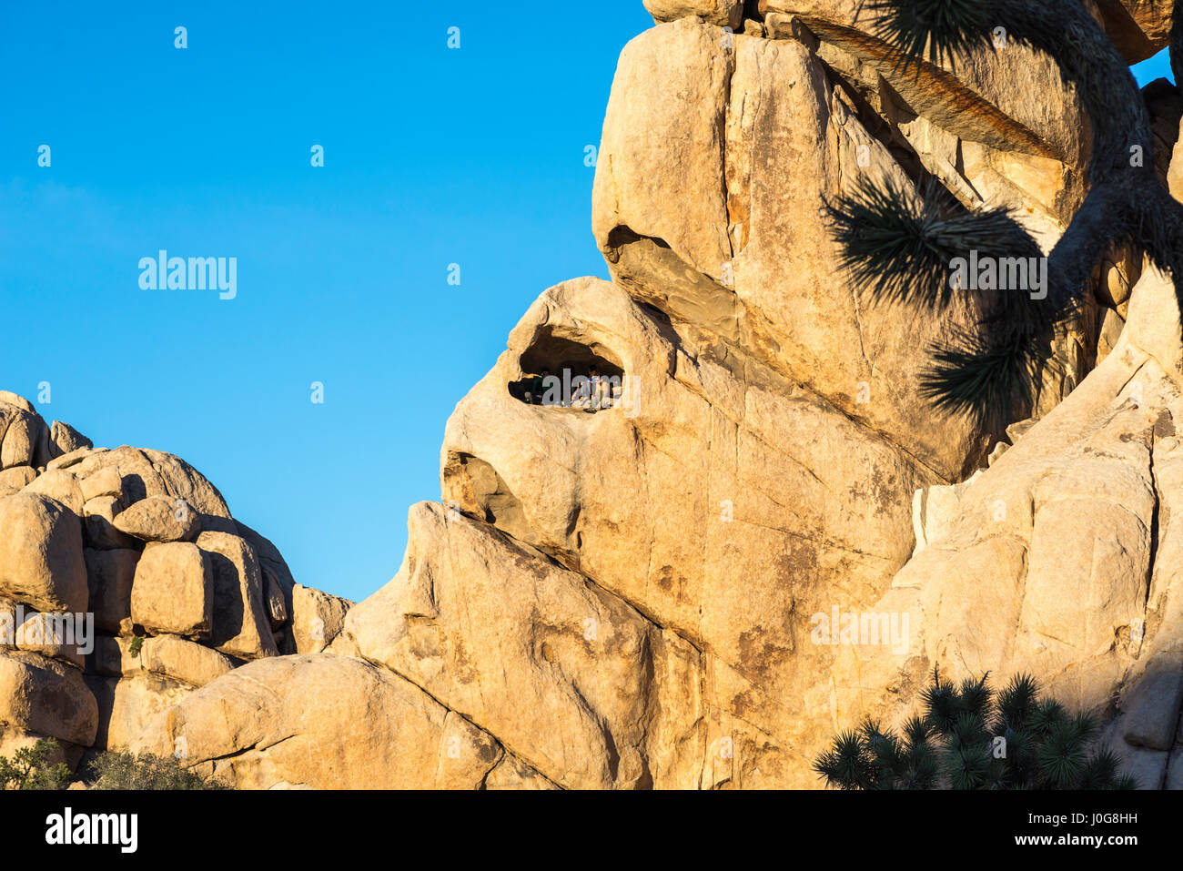Group of people sitting in an alcove in a rock formation. Joshua Tree ...