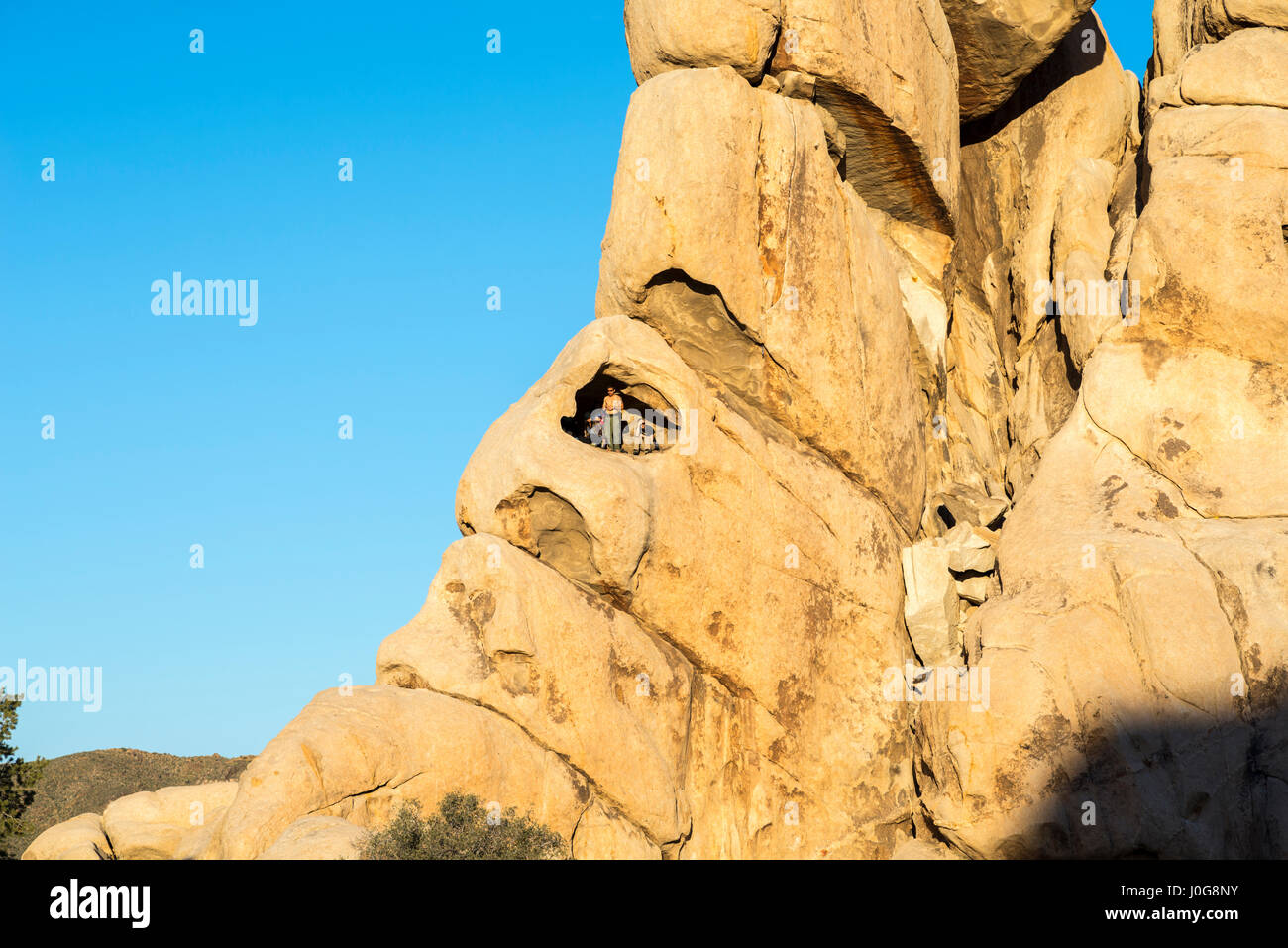 Group of people sitting in an alcove in a rock formation. Joshua Tree ...