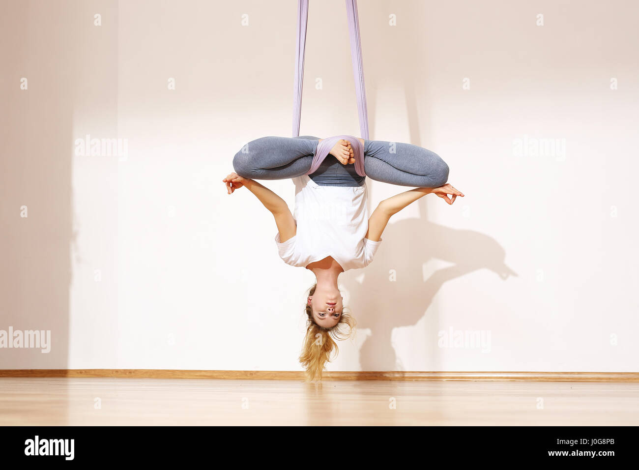 A woman is practicing yoga on a hose, aerial yoga Meditation. Woman ...