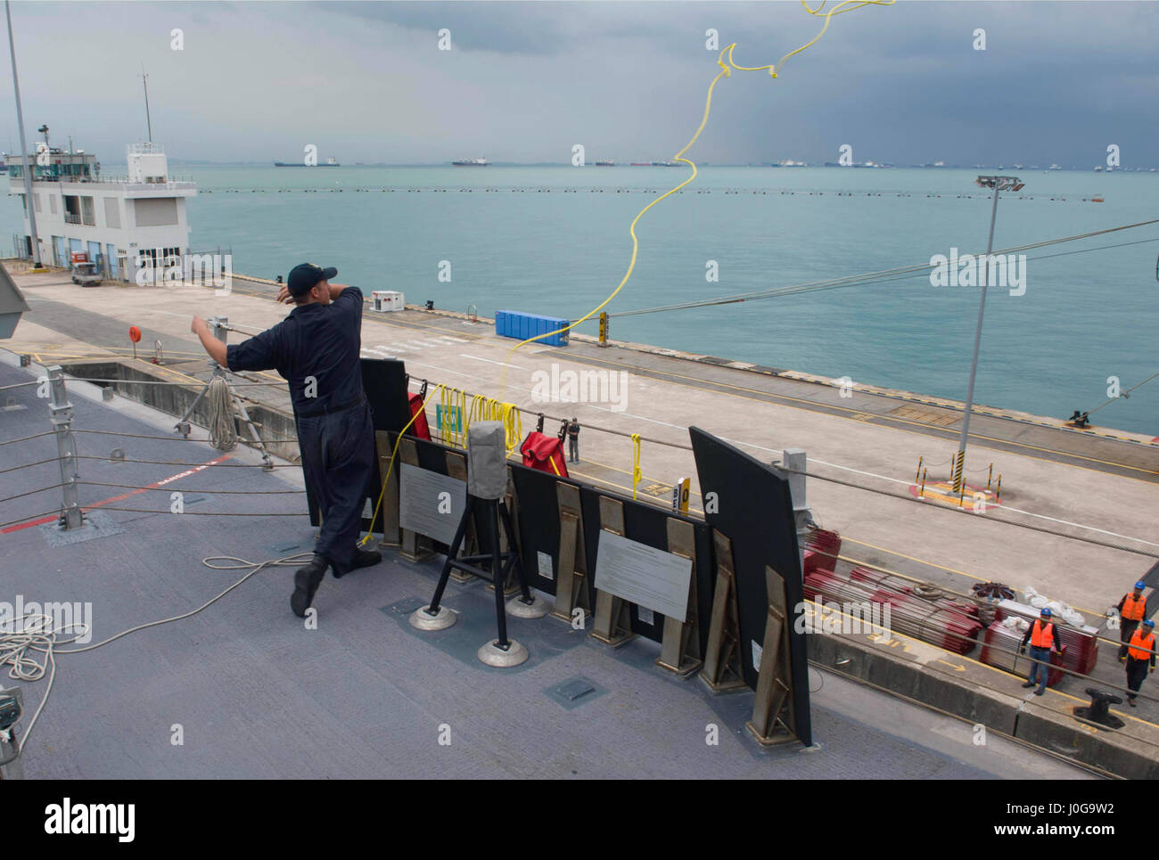 A sailor throws a heaving line to pier line handlers as the littoral ...
