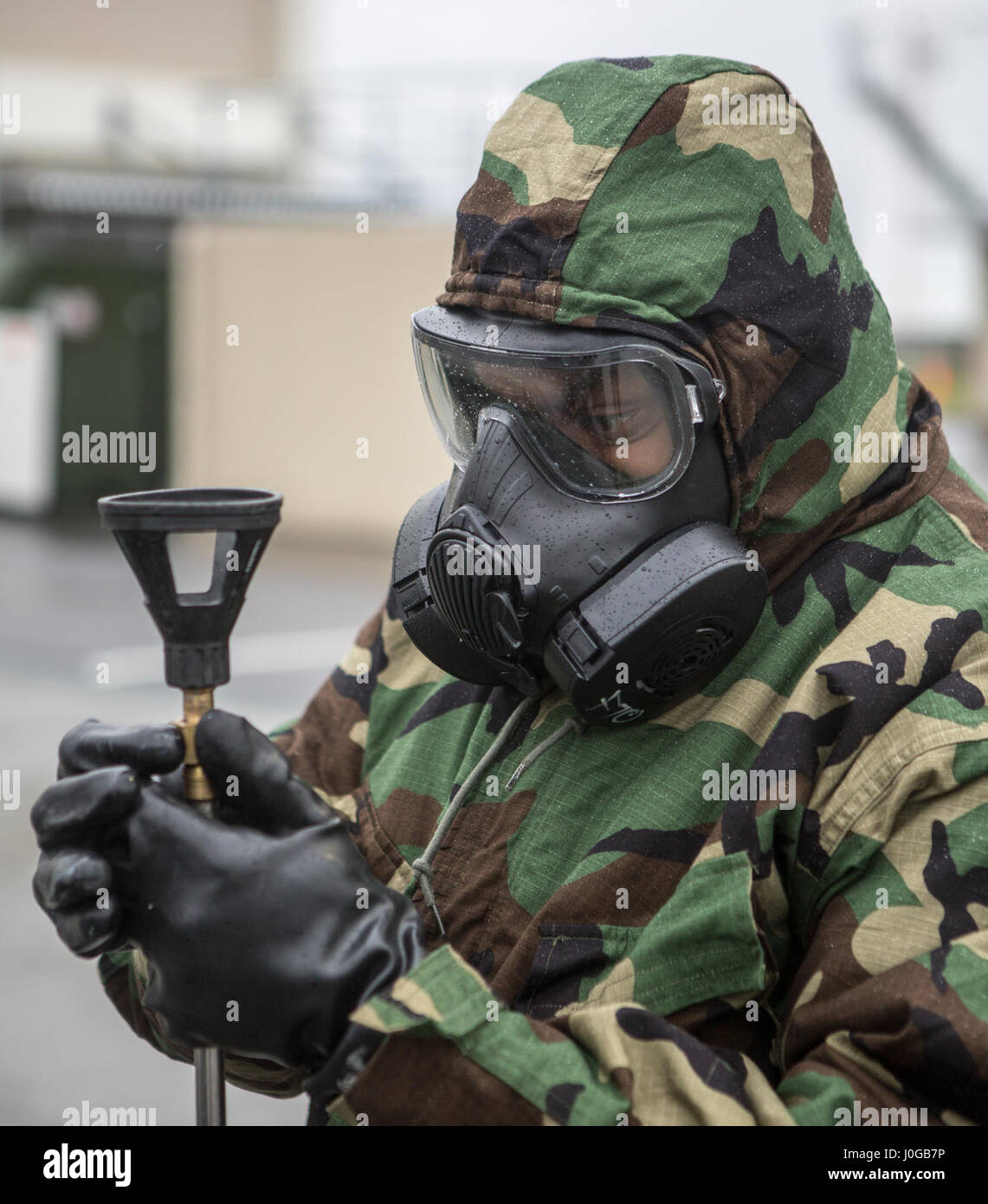 A Marine assembles a hose to conduct aircraft decontamination using an ...