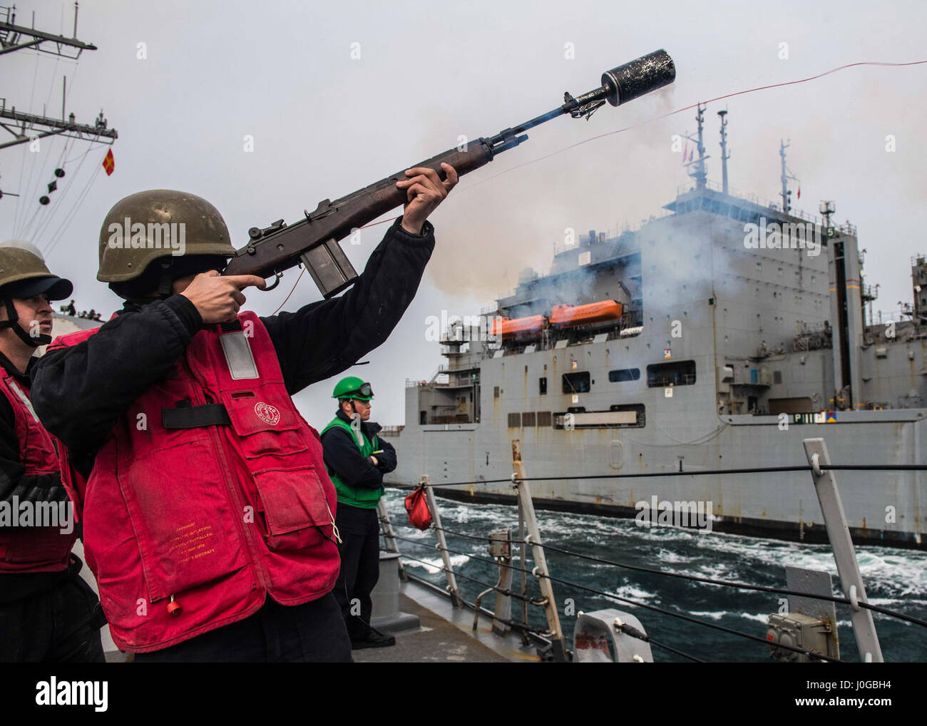 A Fire Controlman aboard USS Barry fires a shot line to the USNS ...