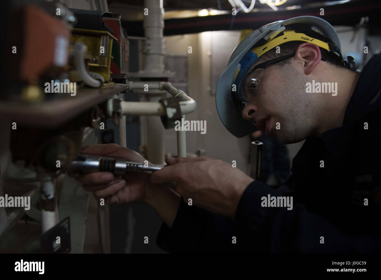 A Damage Controlman replaces a solenoid-operated pilot valve on the ...