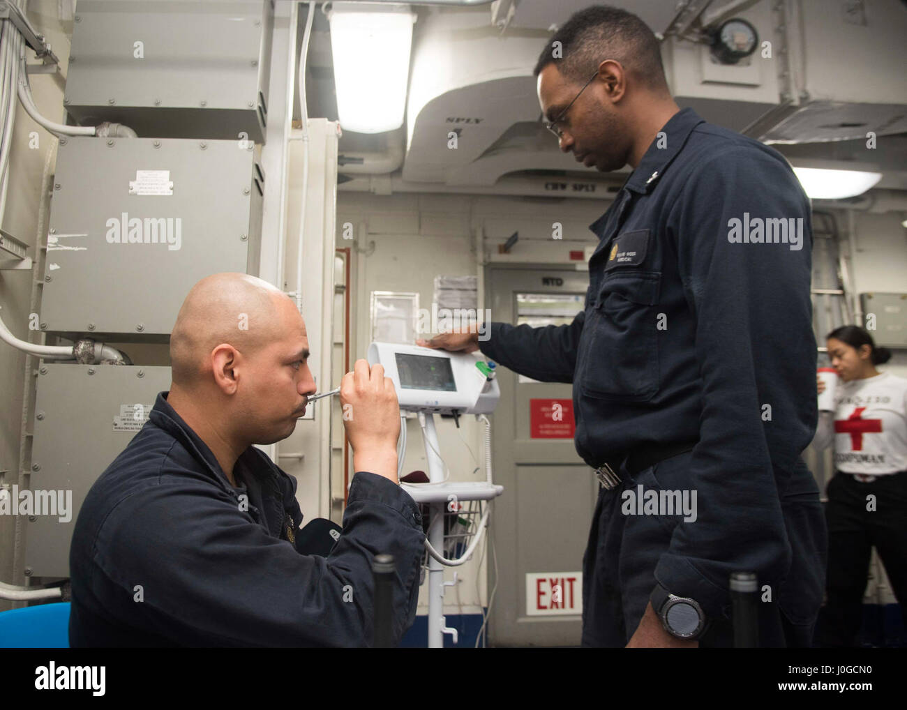 Hospital Corpsman measures crew member temperature in the medical space ...
