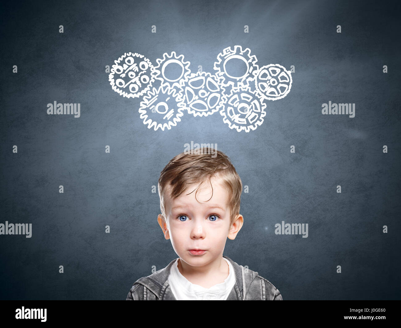 Smart child thinks of looking at gears Stock Photo - Alamy
