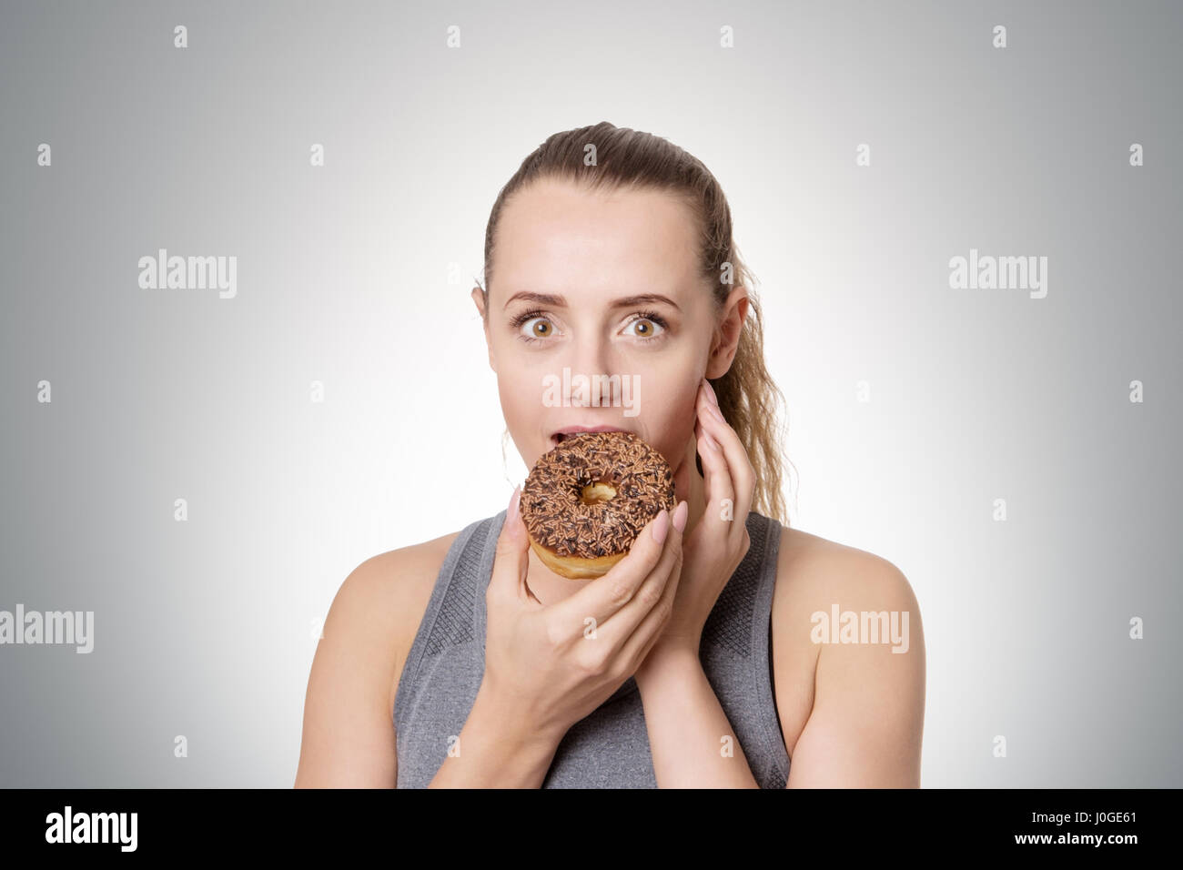 fitness woman eating a cheeky donut Stock Photo - Alamy