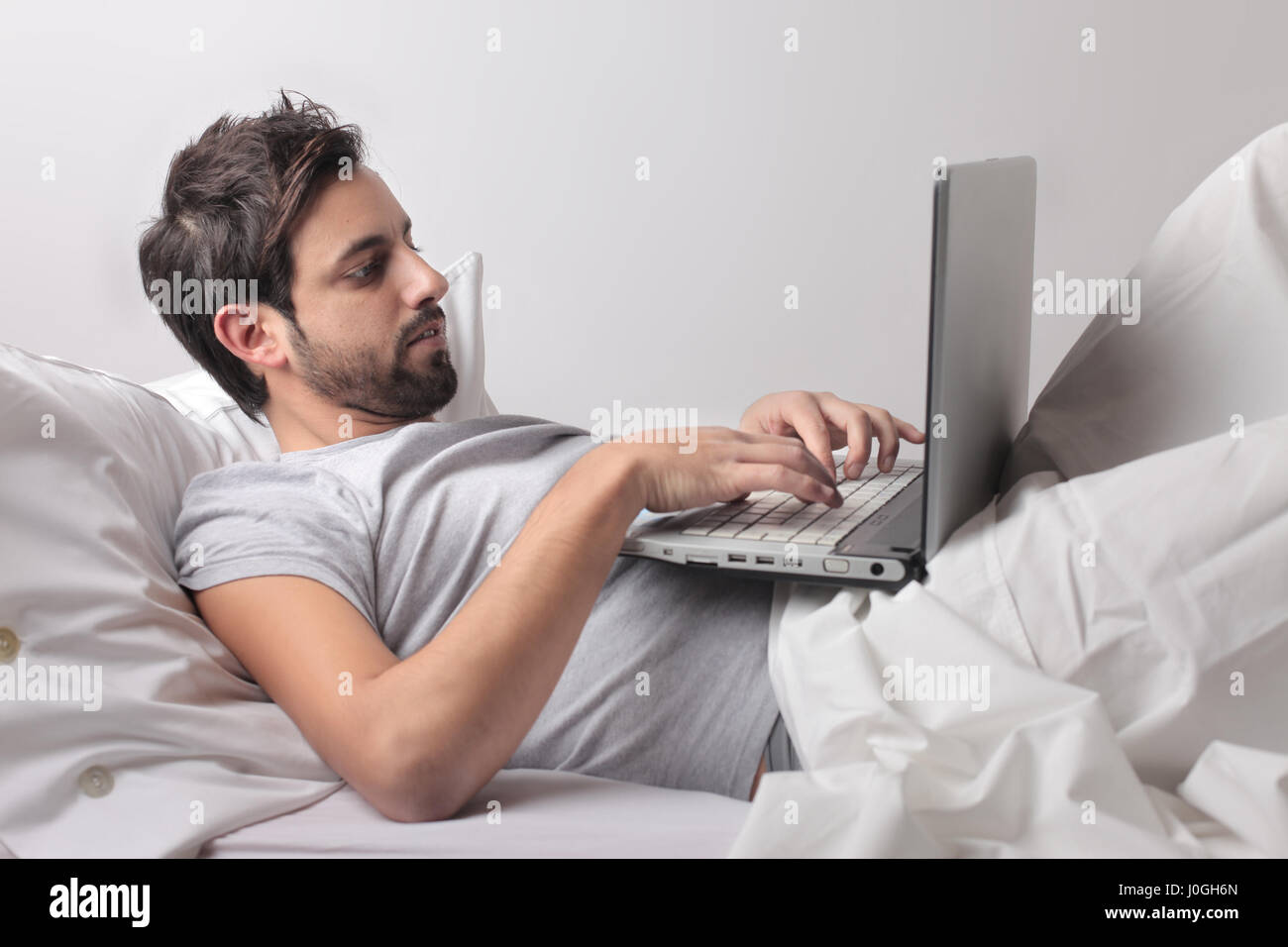 Man working on laptop in bed Stock Photo - Alamy