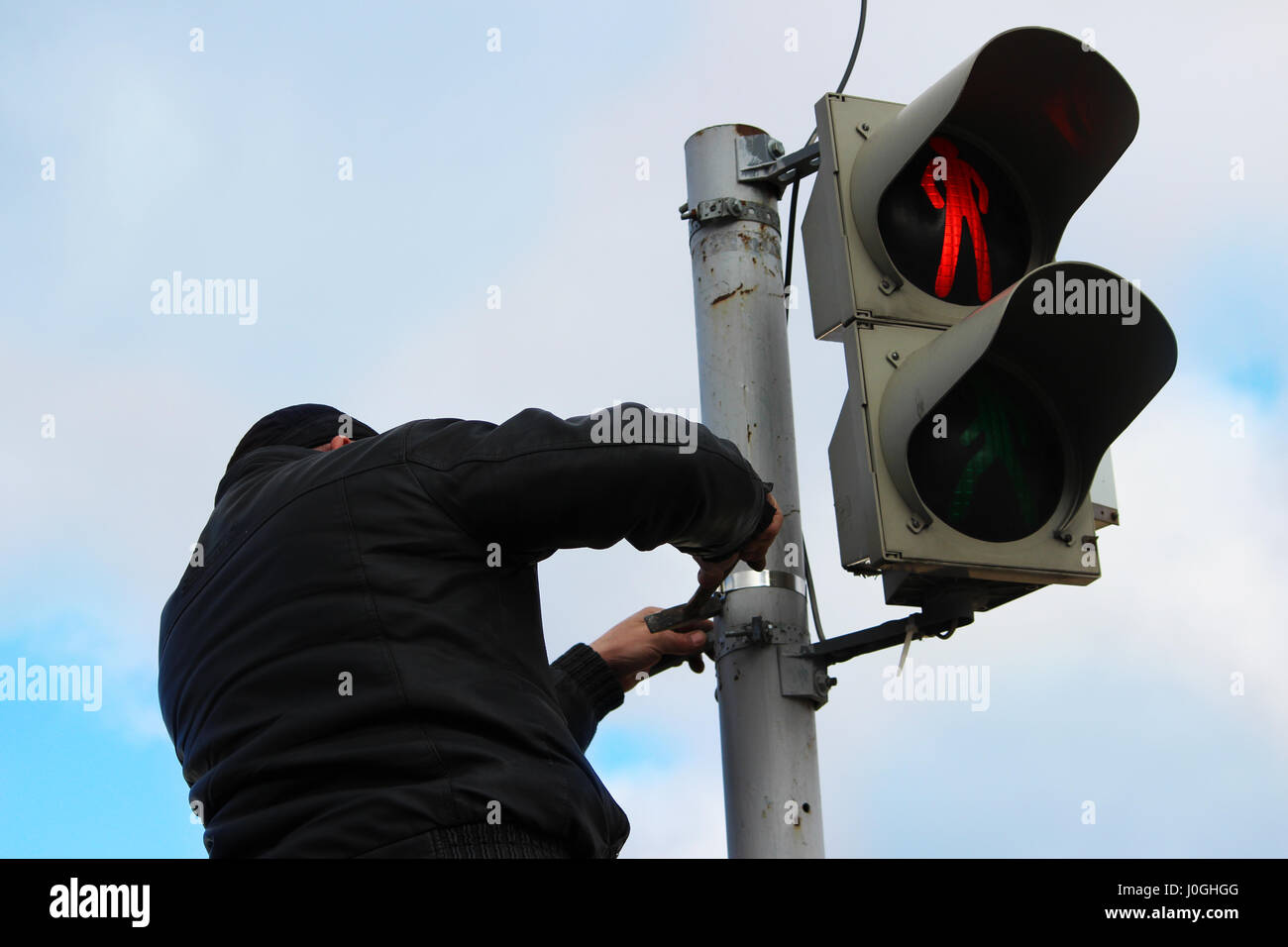 The worker prepares a fastening for the road sign pedestrian crossing ...