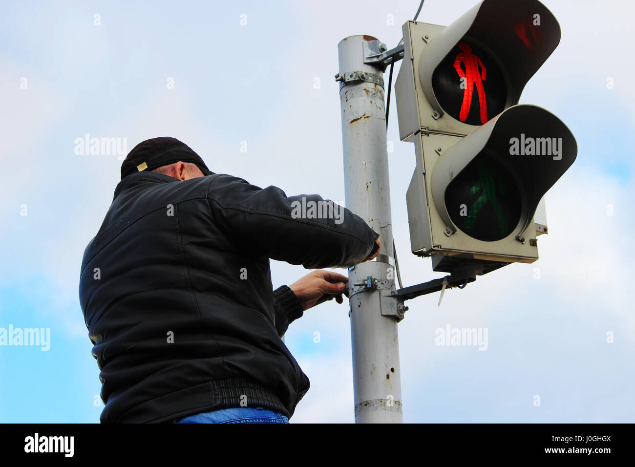 The worker prepares a fastening for the road sign pedestrian crossing ...
