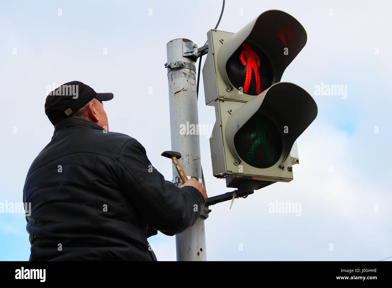 The worker prepares a fastening for the road sign pedestrian crossing ...