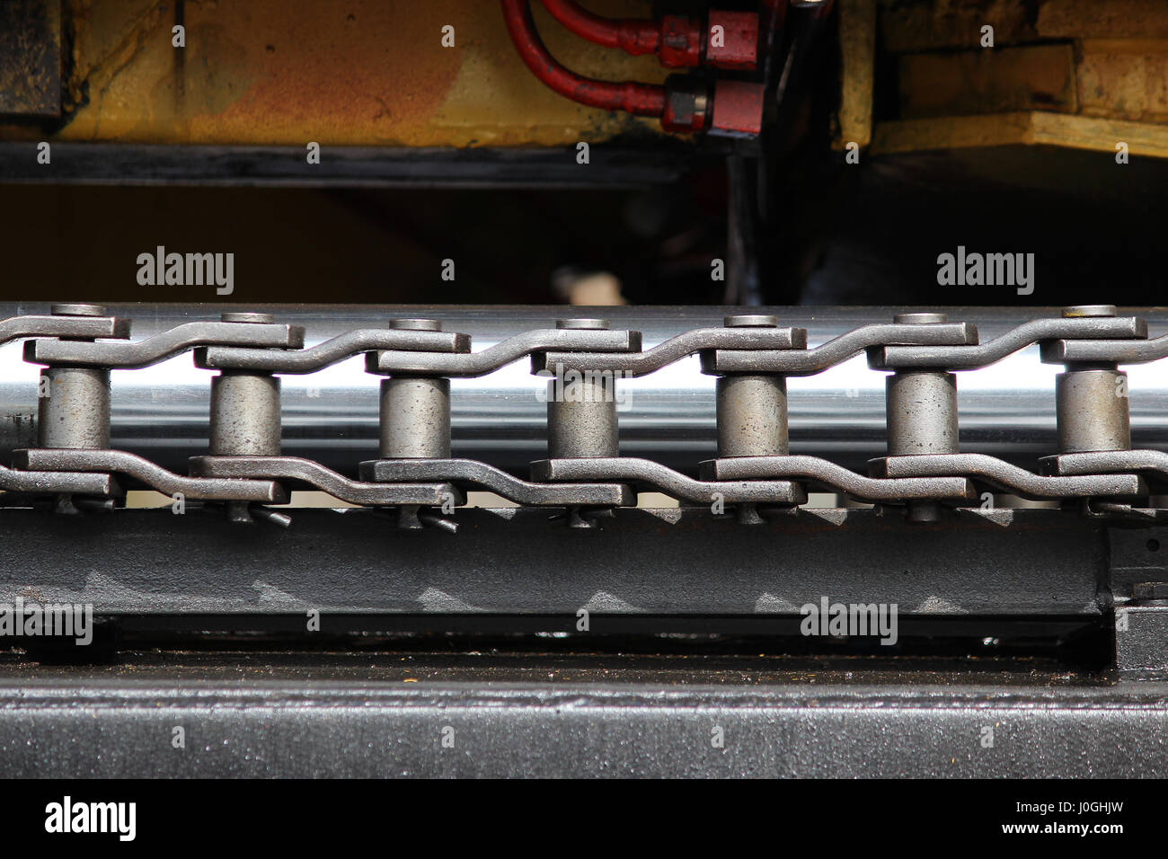 The device of a yellow loader on the railway. Gray steel chain links ...