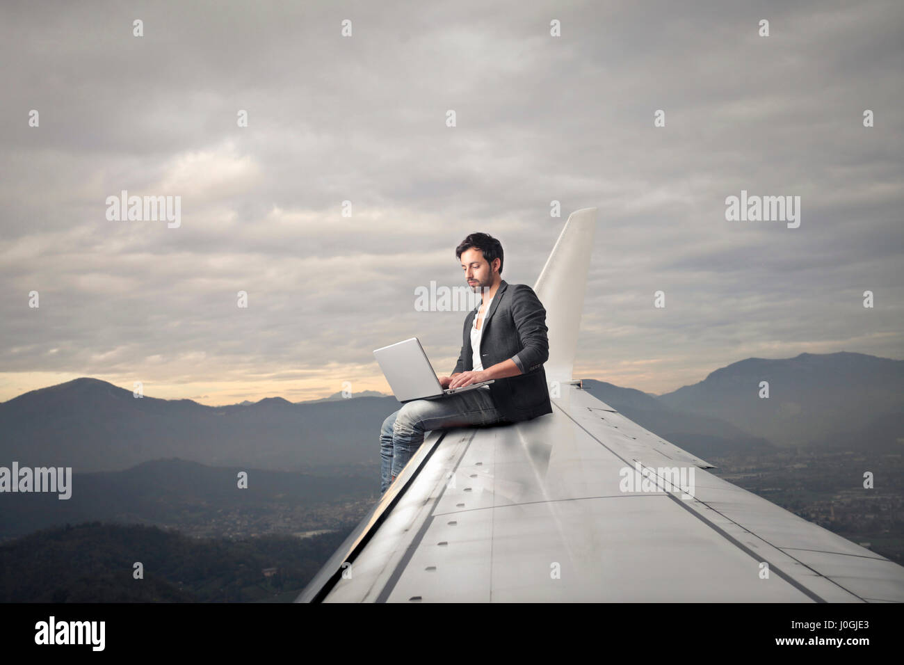 Man with laptop sitting on airplane's wing Stock Photo - Alamy