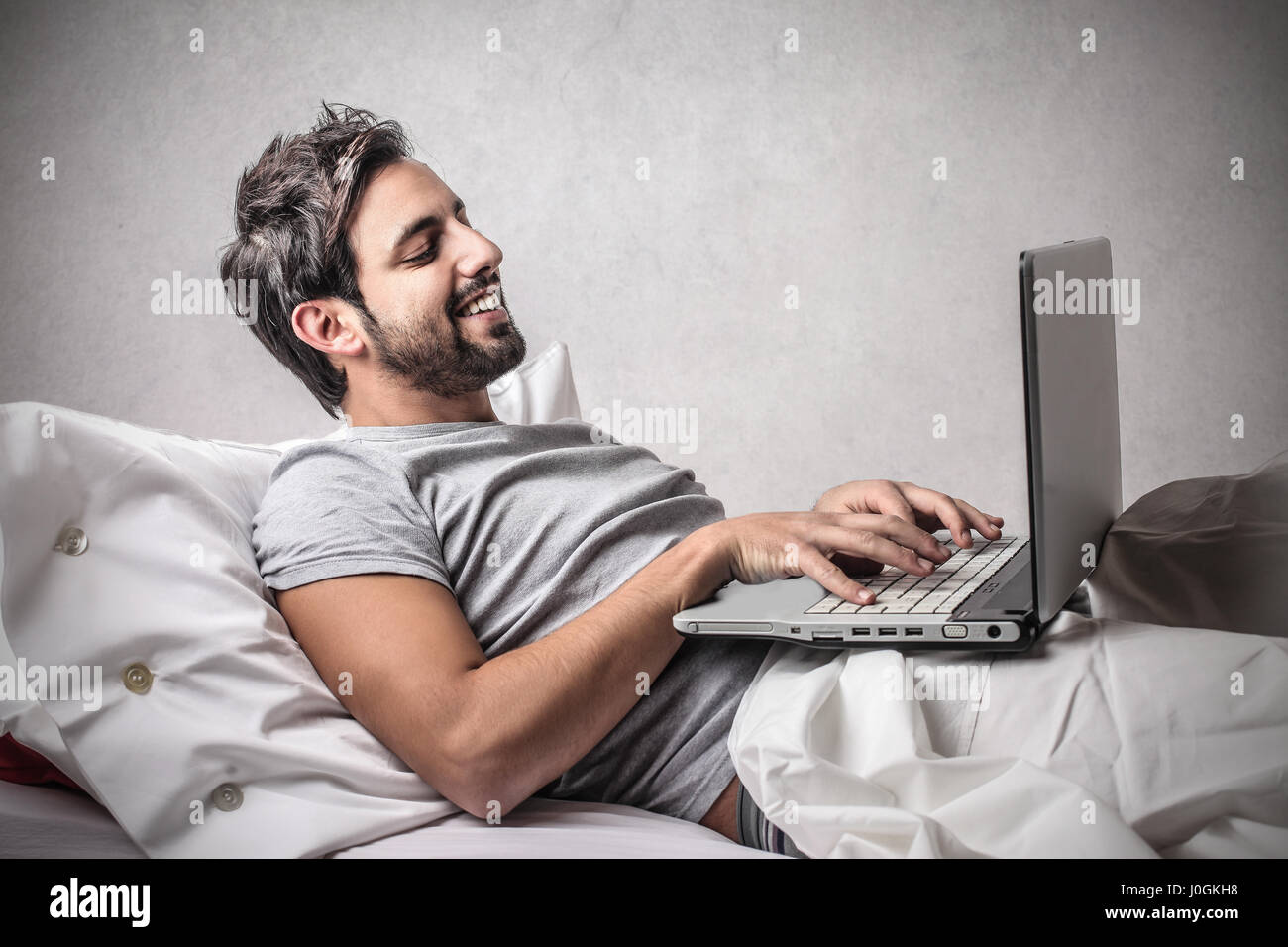 Man working on laptop in bed Stock Photo - Alamy