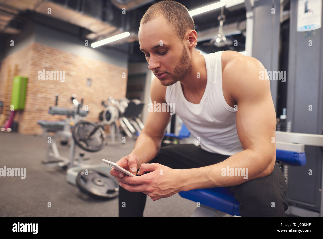 Muscular young man using cell phone at gym Stock Photo - Alamy