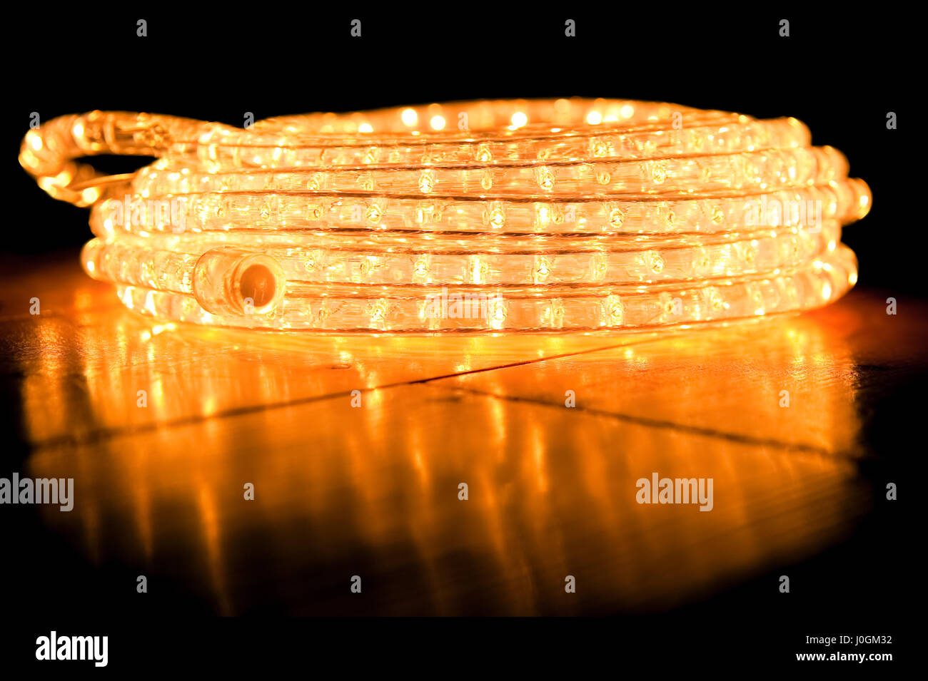 festive tube rope light coiled on a reflective hardwood floor Stock ...