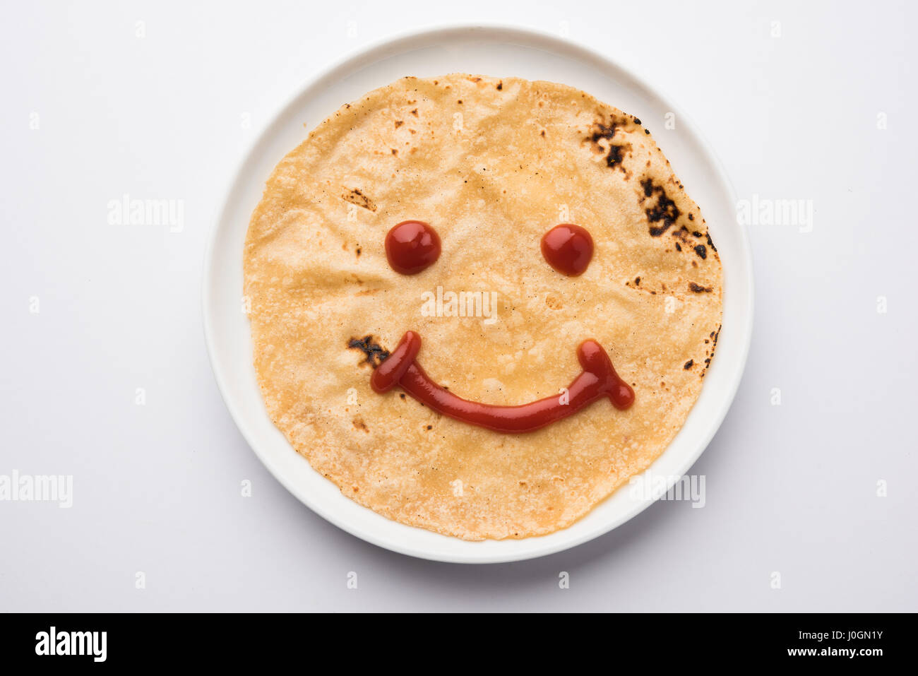 ketchup or fruit jelly/jam smile emoticon over indian bread / chapati ...